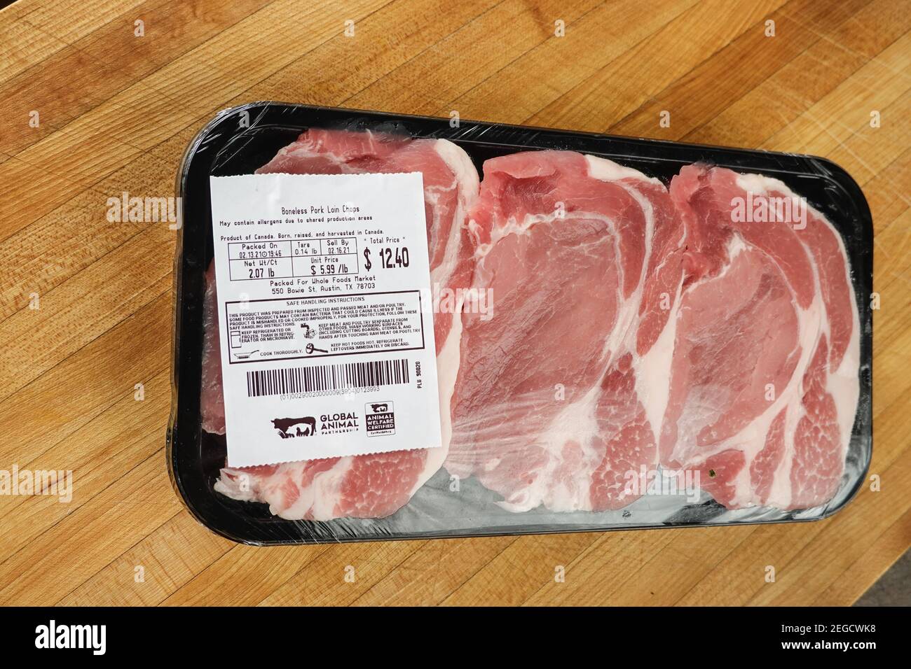 packaged Raw boneless loin Pork chops on a wood kitchen cutting board ...