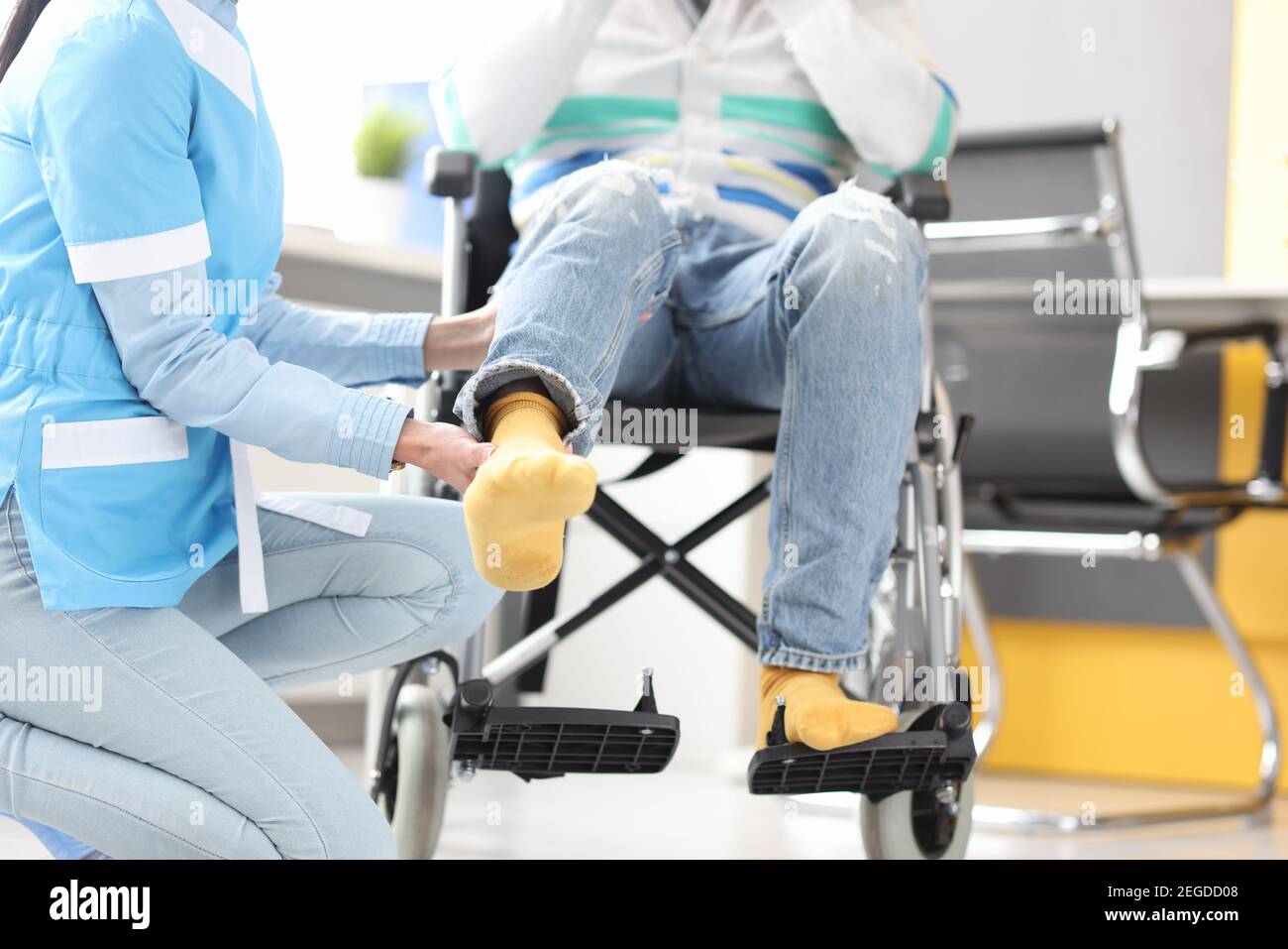 Rehabilitation doctor helping to lift leg of patient in wheelchair ...