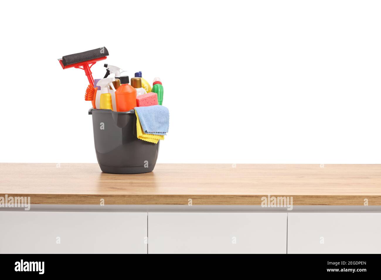 Bucket full of cleaning supplies on a wooden counter isolated on white ...