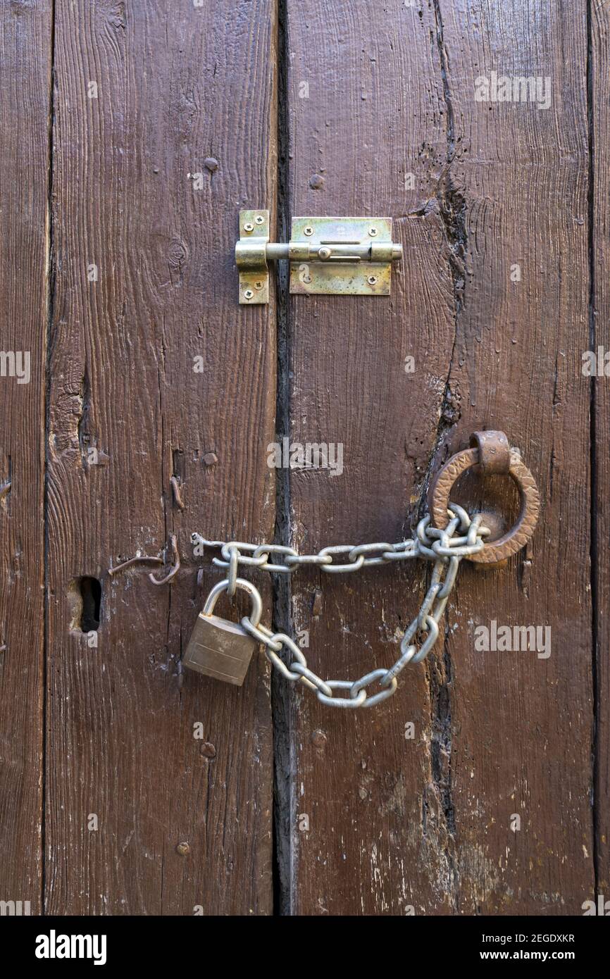 Wooden rustic door locked with chains, catch, and padlock Stock Photo ...