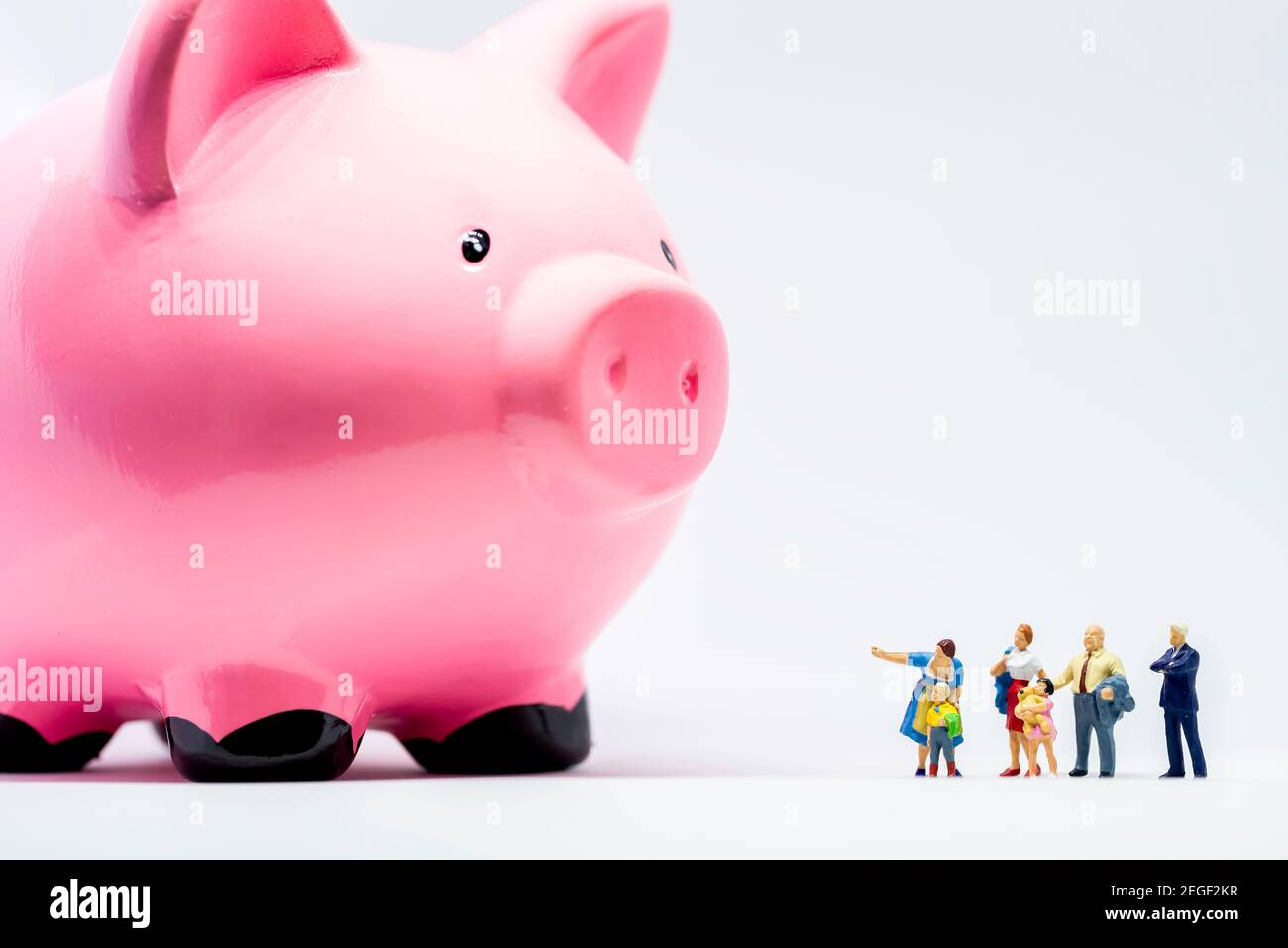 Miniature people. Two adults showing giant piggy bank to a boy Stock ...