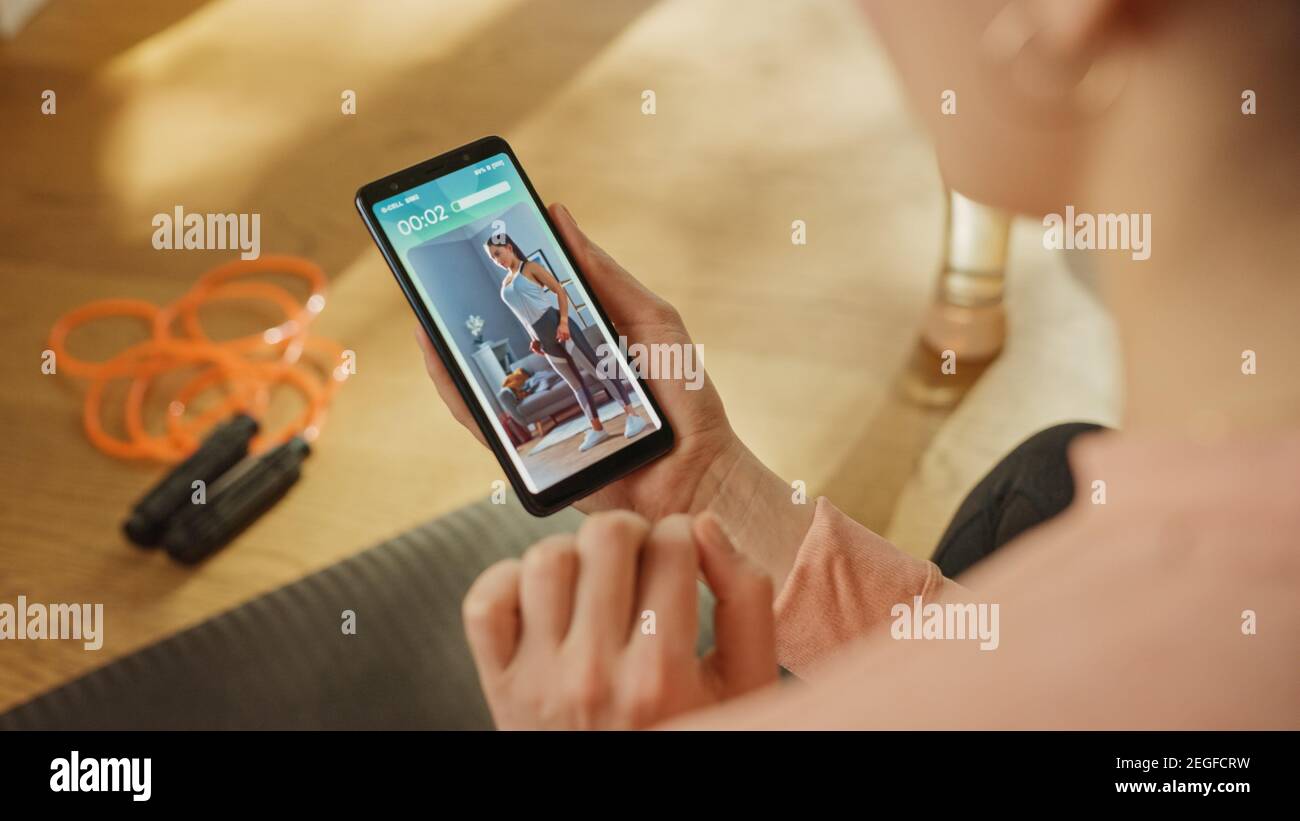 Over Shoulder Shot: Fit Woman Holds Smartphone, Uses Fitness Tracking ...