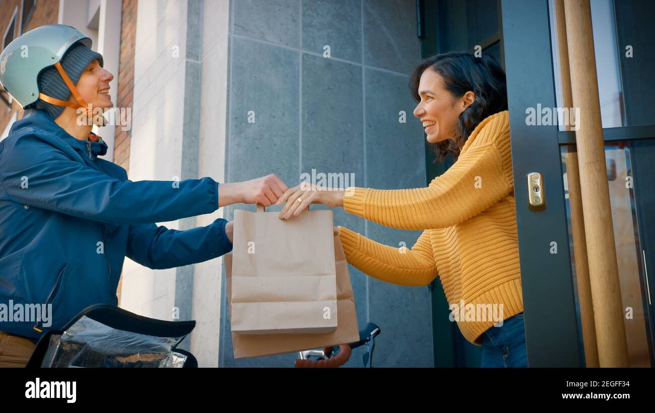 Happy Food Delivery Man on a Bike Delivers Restaurant Order to a ...
