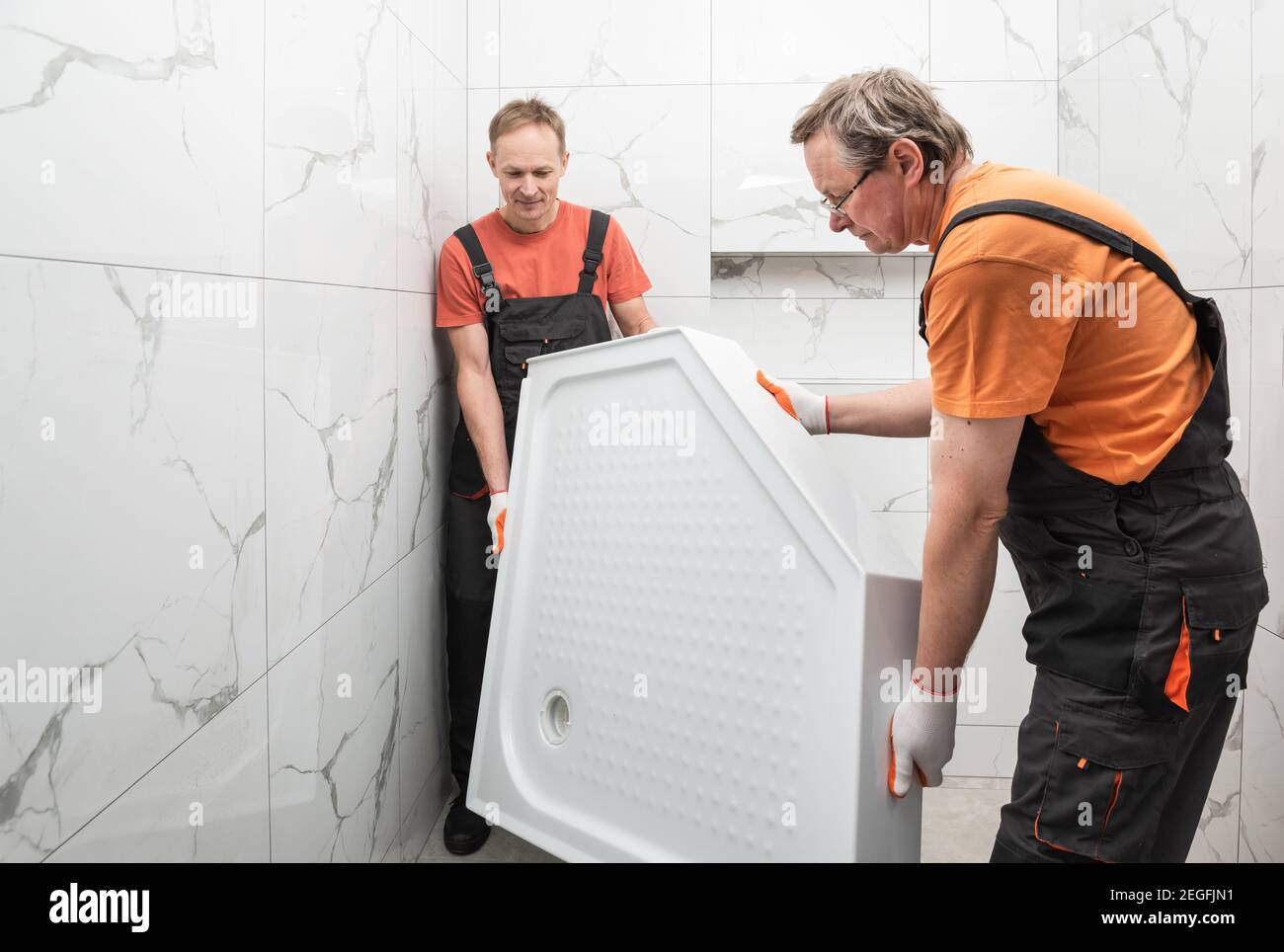 Workers are installing a shower tray in the bathroom Stock Photo - Alamy
