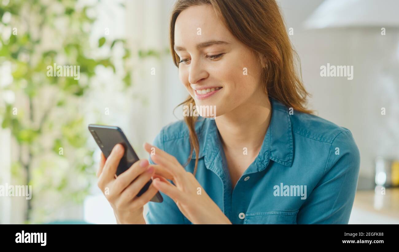 Beautiful Female Using Smartphone in a Bright Sunny Kitchen. She is ...
