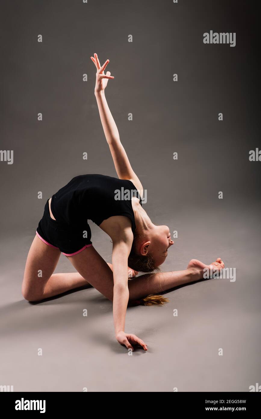 Little girl doing gymnastics with hoop, ball and split isolated on grey ...