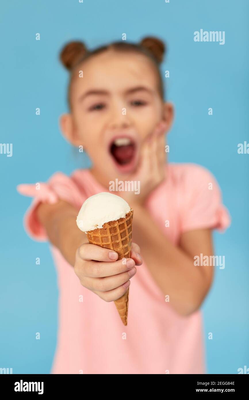 surprised little girl holding vanilla ice cream in a waffle cone on ...