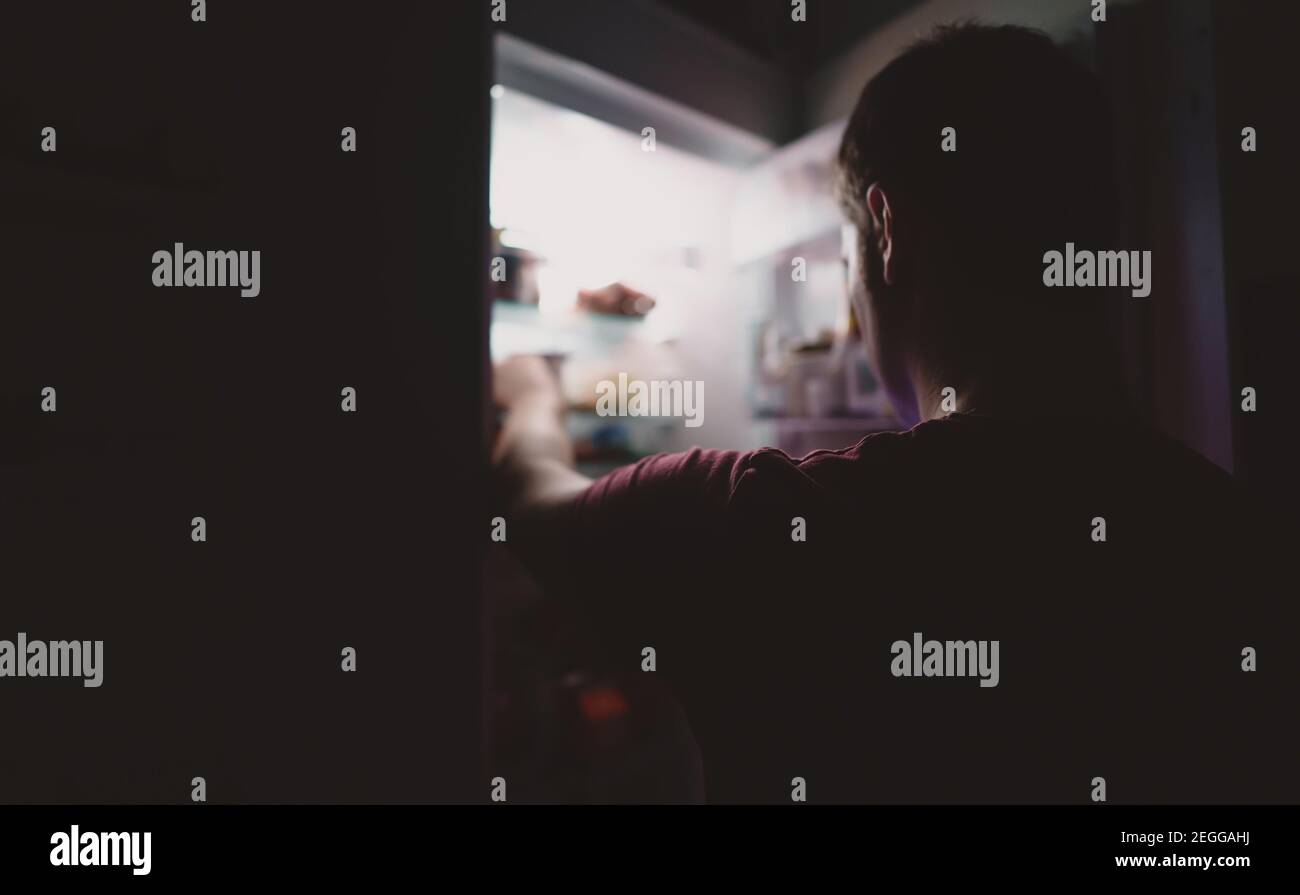 Man looking for food in refrigerator at night Stock Photo - Alamy