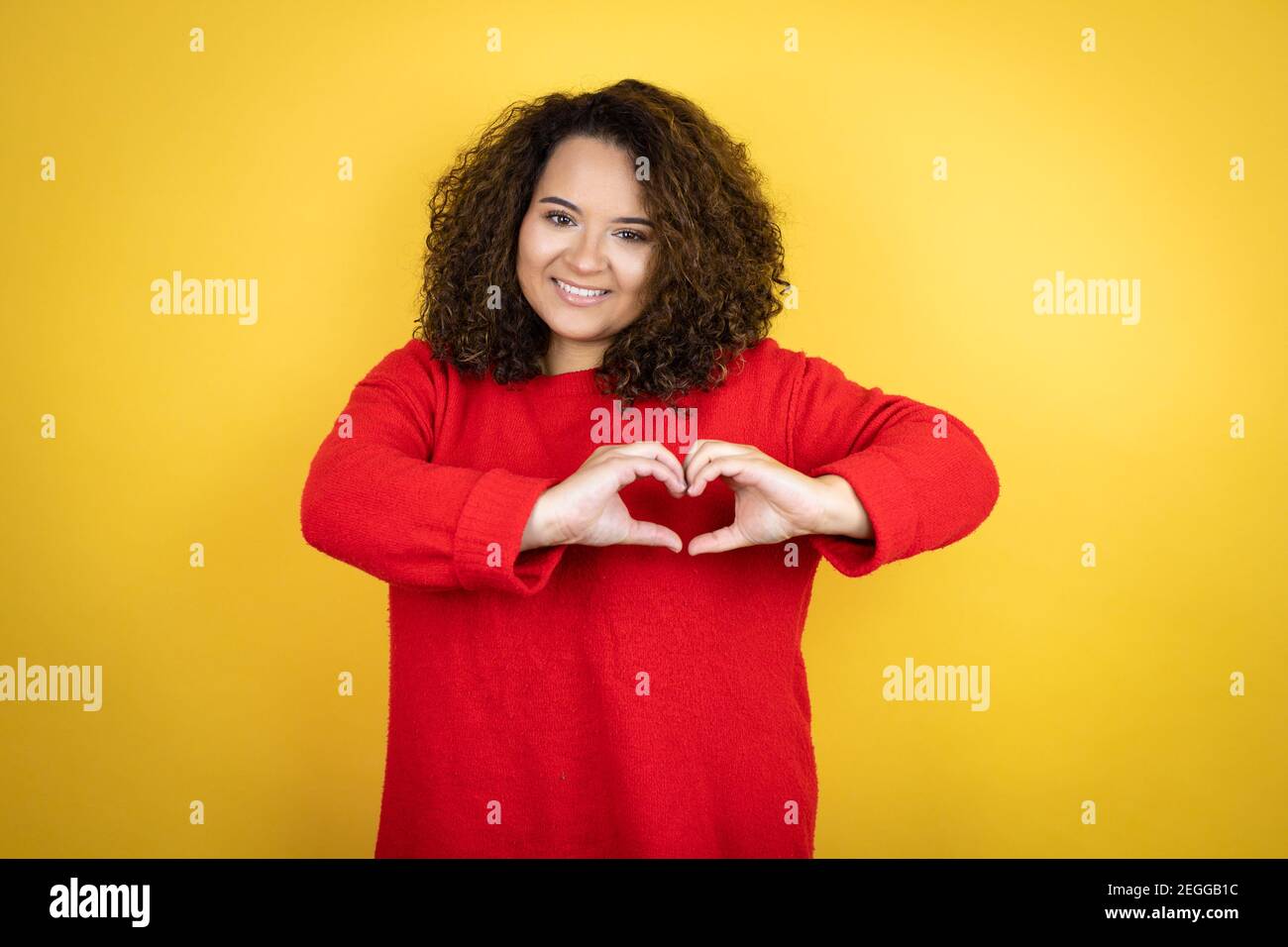 Young african american woman wearing red sweater over yellow background ...