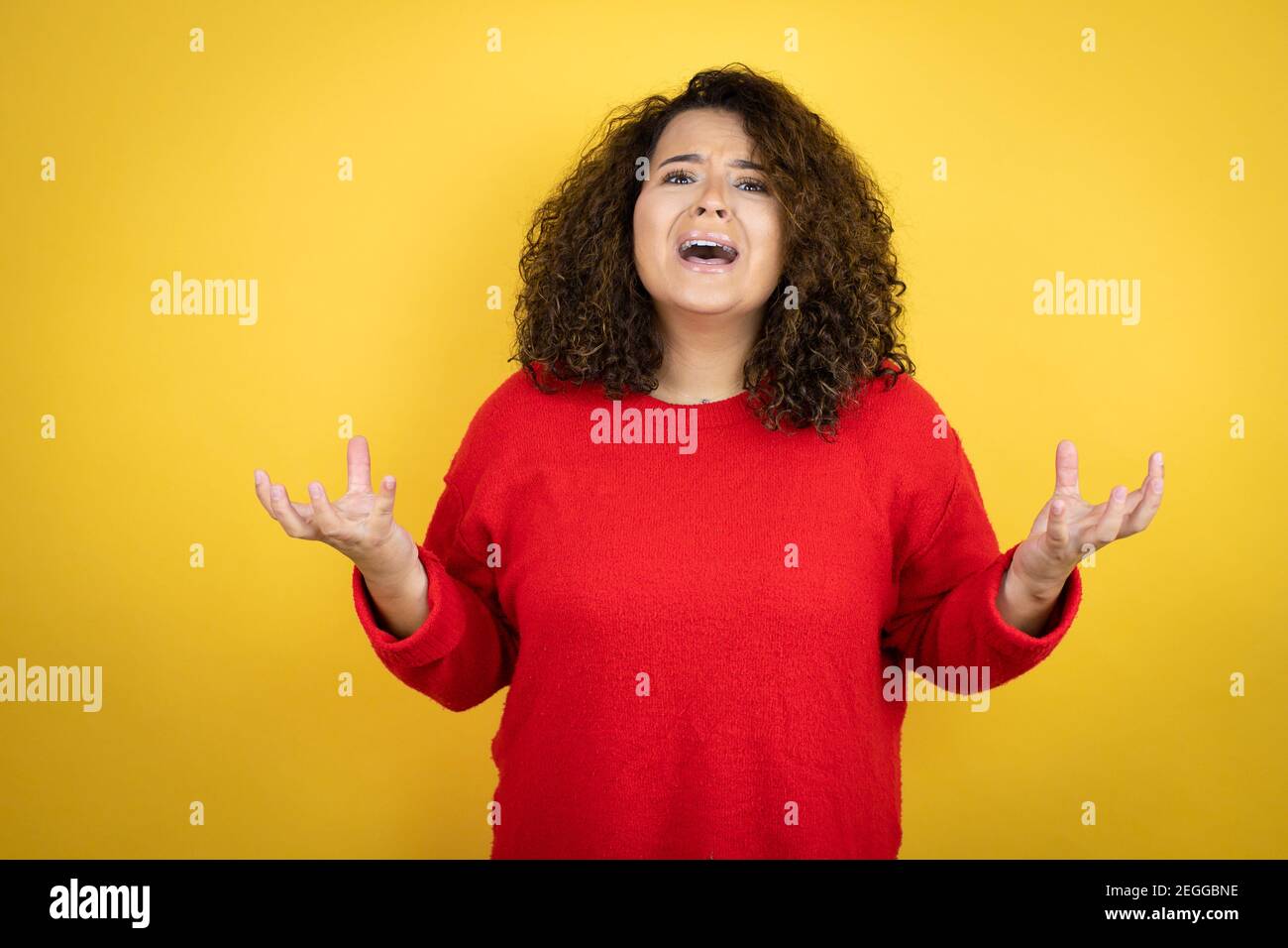 Young african american woman wearing red sweater over yellow background ...