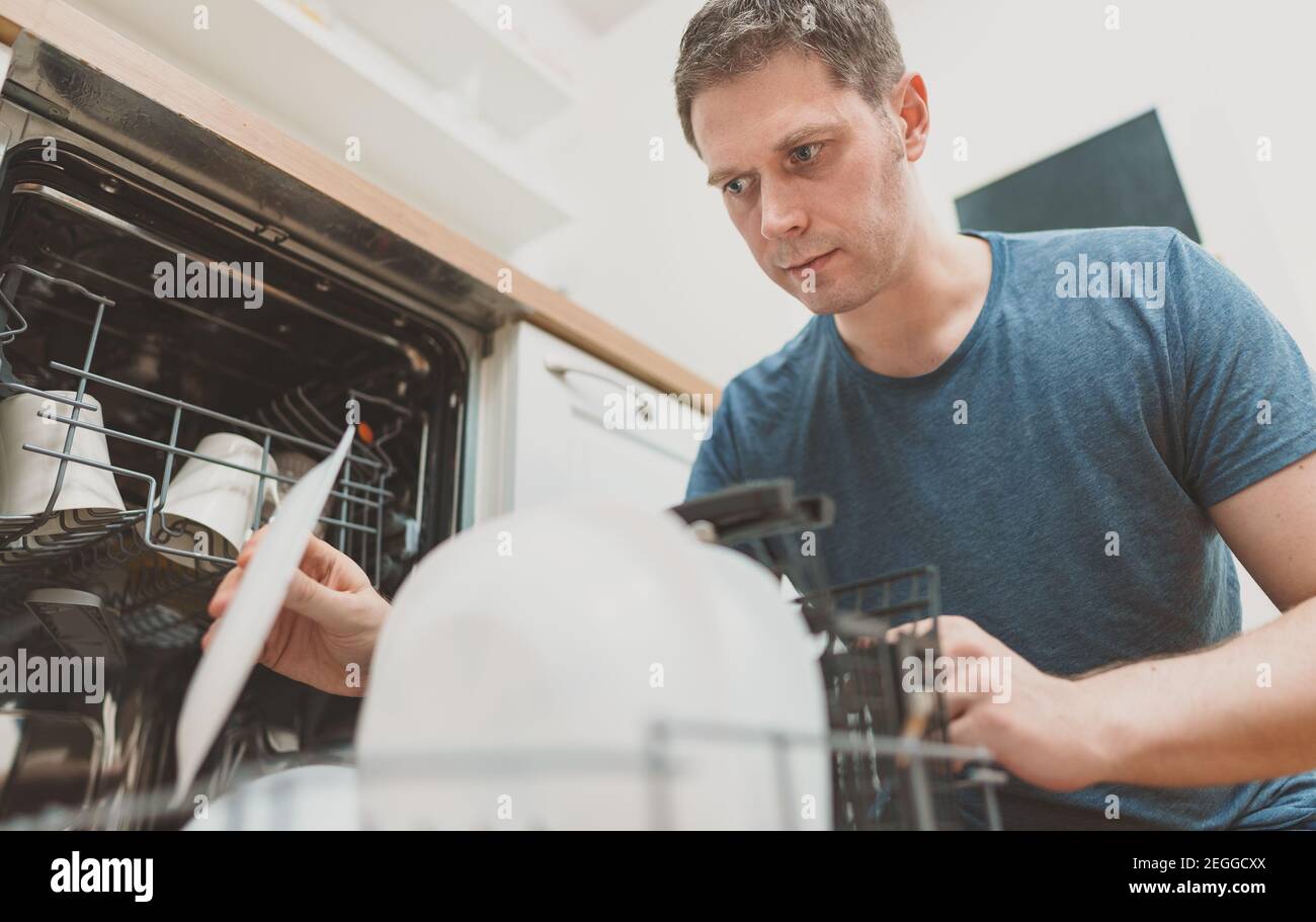 Man puts plate to the dishwasher in the kitchen Stock Photo - Alamy