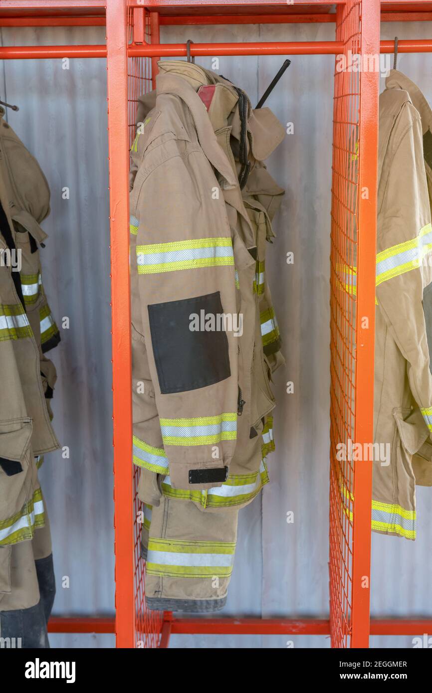 Vertical shot of a metal rack with firefighter uniforms in a station ...