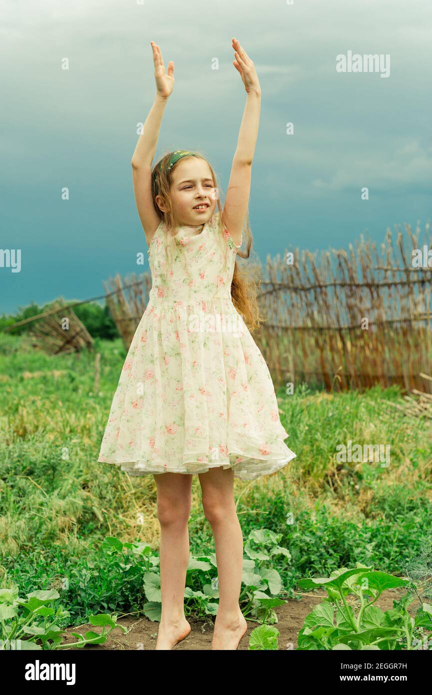 A little girl with hands raised up in nature shows freedom. Teenage ...