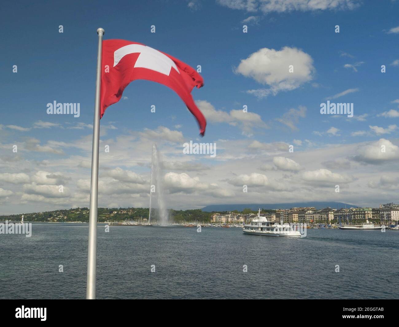 a swiss flag with a ferry and the famous water jet in the background at ...