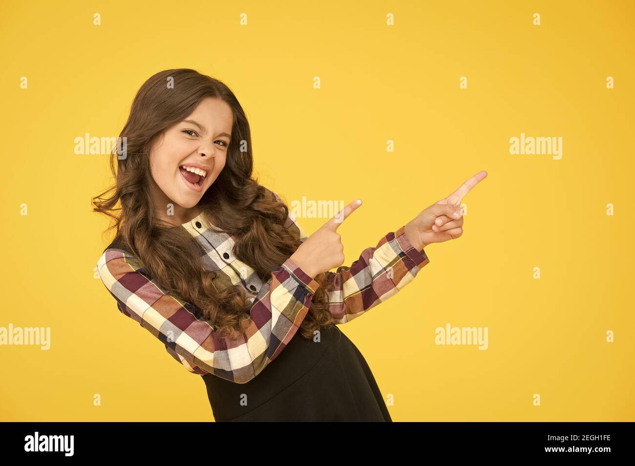 Dont leave without it. Happy child pointing at yellow background ...