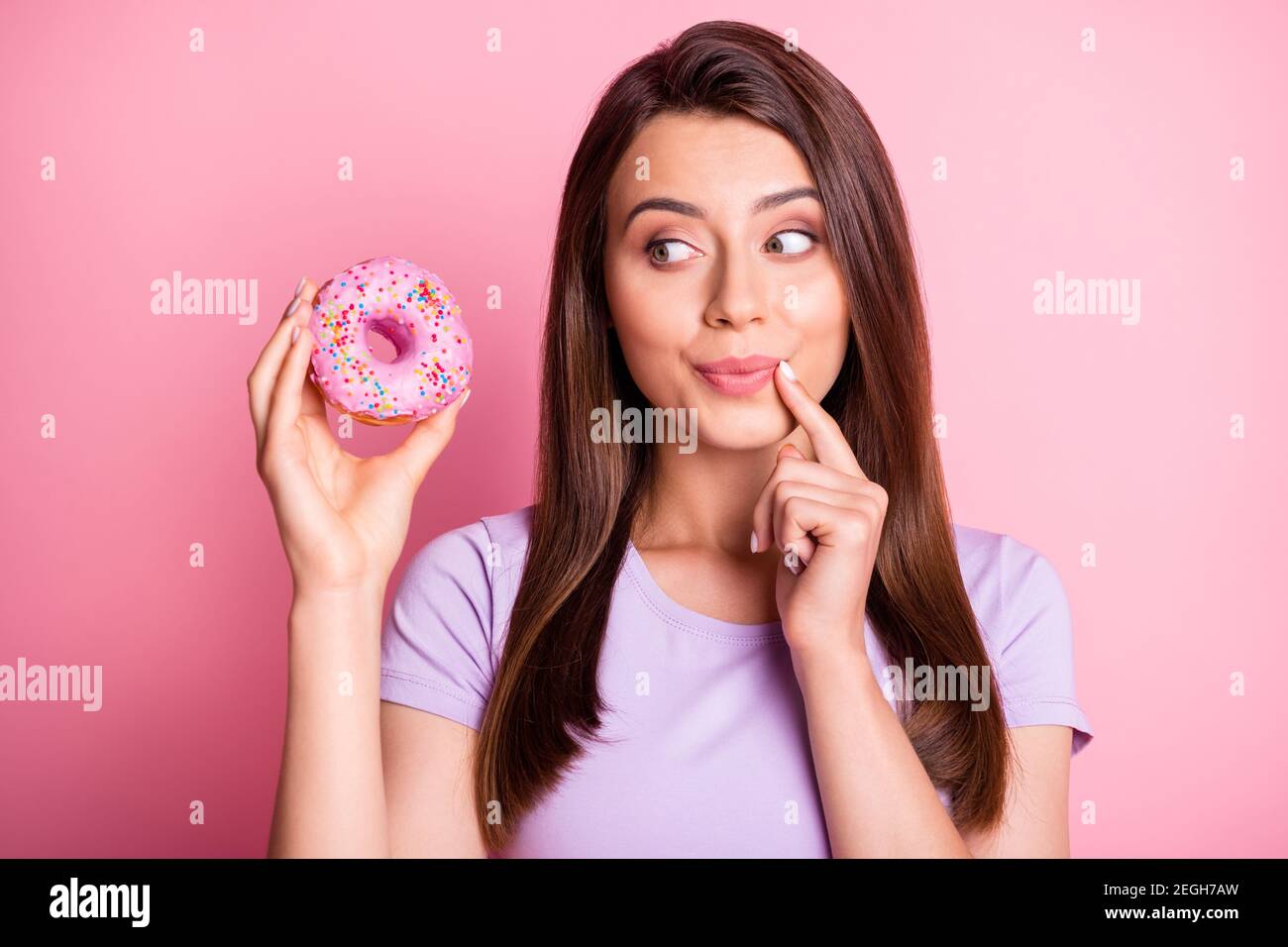 Photo portrait of curious girl holding donut in one hand isolated on ...