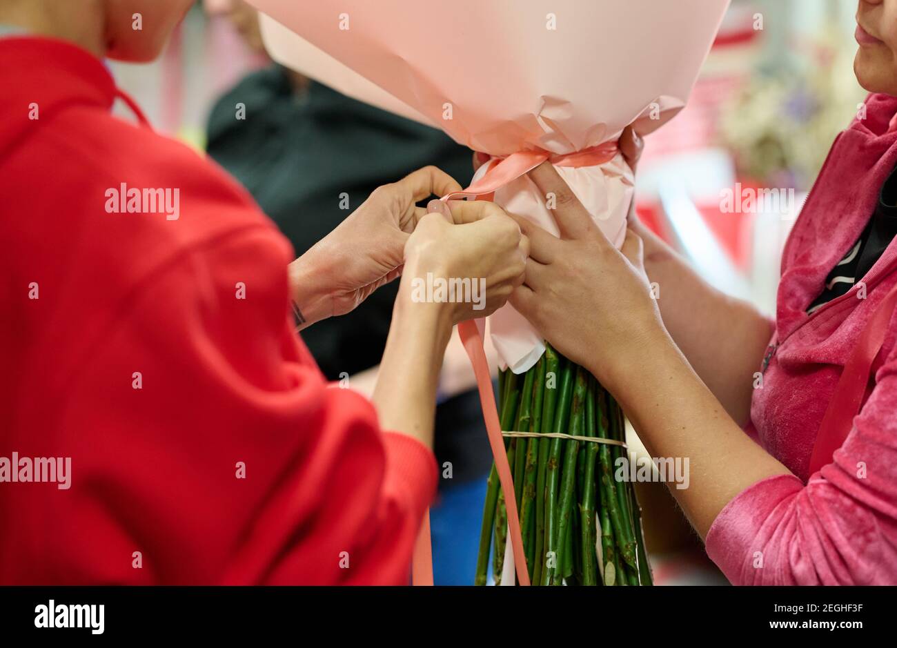 Bouquet assembly process in the workshop, two florists packing bouquet ...