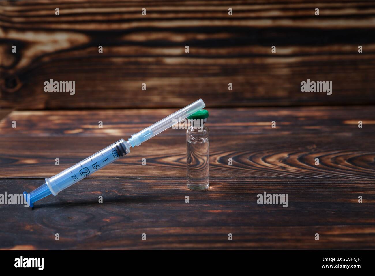 Medical vials for injection and syringe, on a dark brown wooden table ...