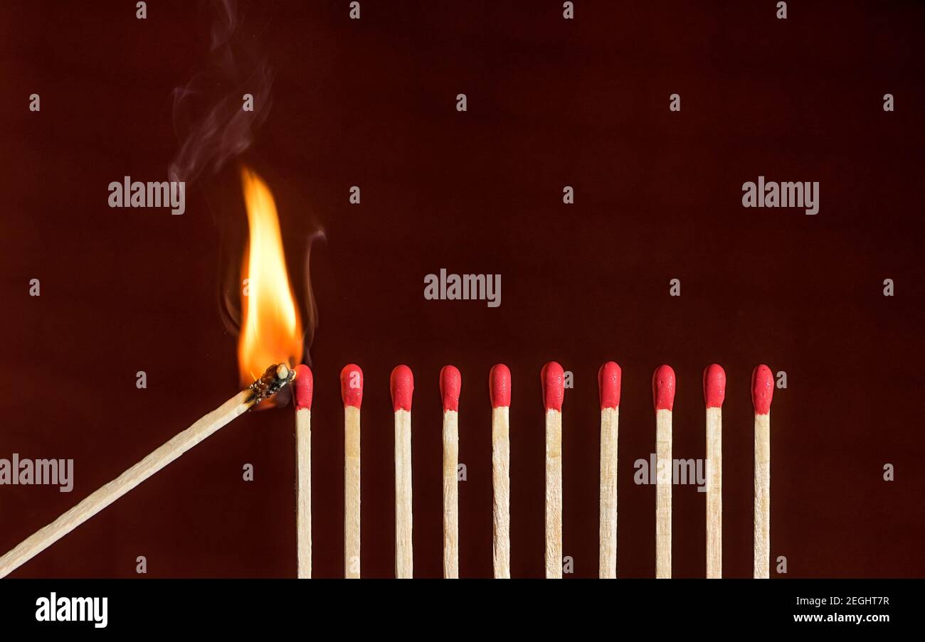 Lit match next to a row of unlit matches. Red phosphorus matches on ...