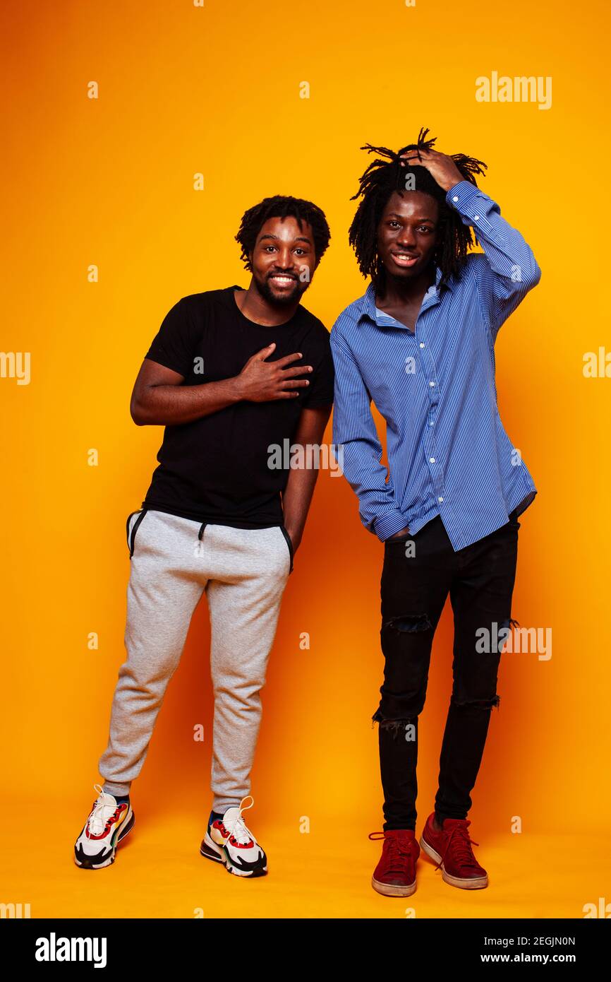 two african american guys posing cheerful together on yellow background ...