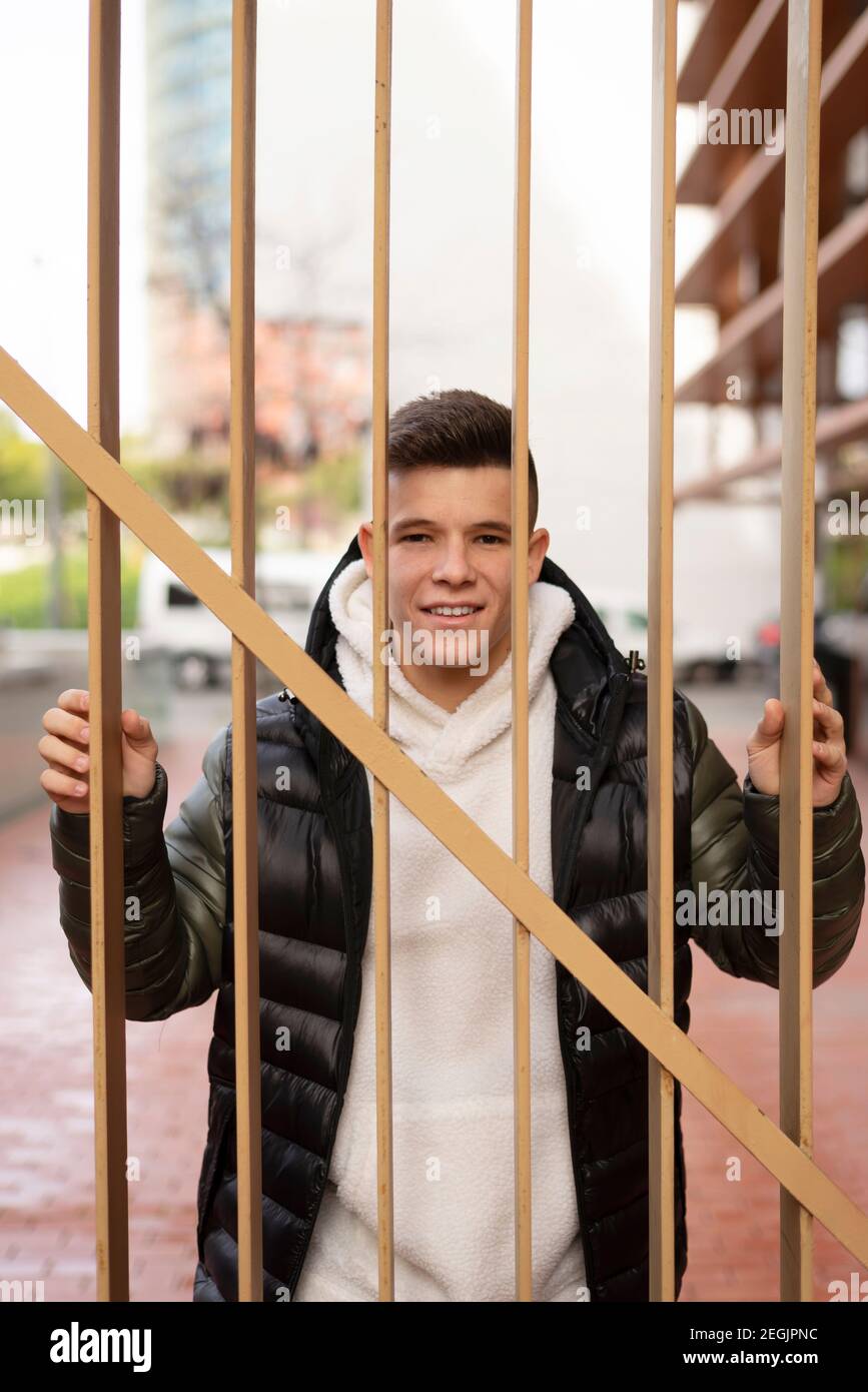 Young guy standing behind a metal fence while looking camera Stock ...