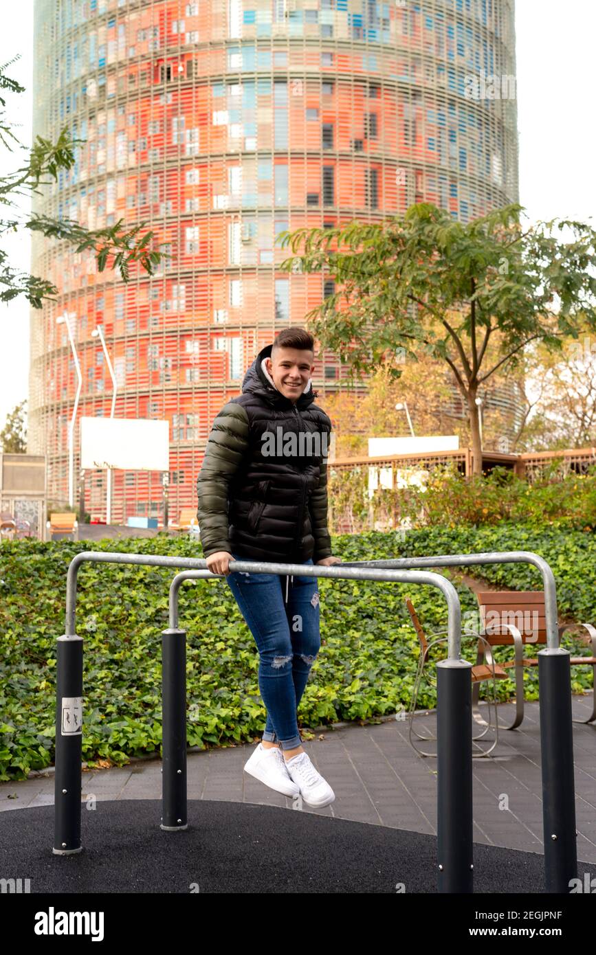 Young guy joining parallel bars outdoors while looking camera outdoors ...