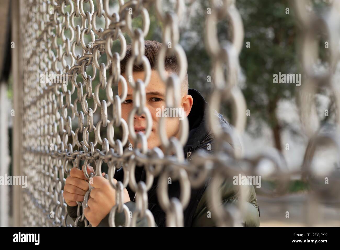 Young guy standing behind a metal fence while looking camera Stock ...