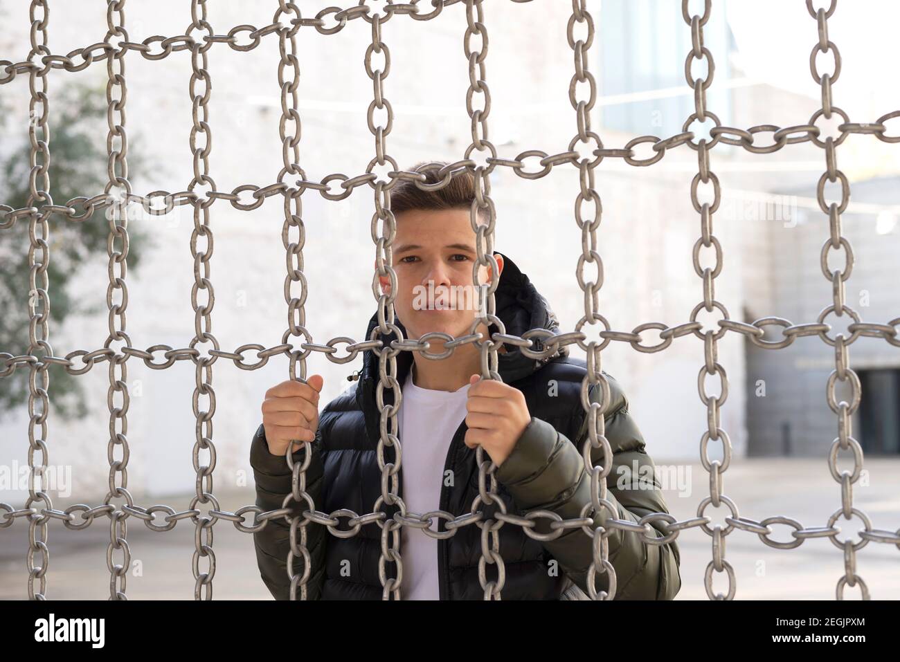 Young guy standing behind a metal fence while looking camera Stock ...