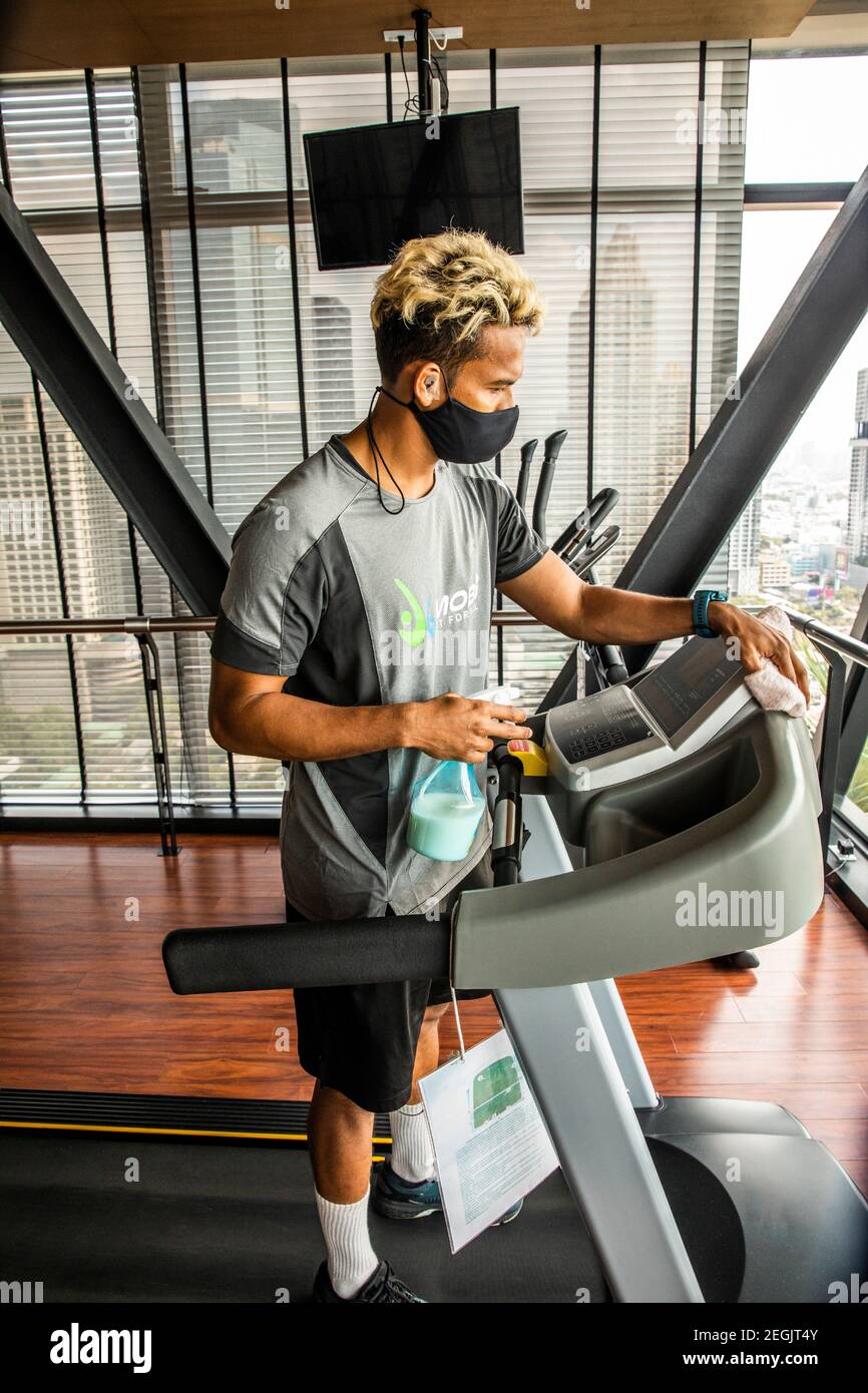 Fitness Trainer Wears and Mask and Cleans Equipment Before-After Use ...