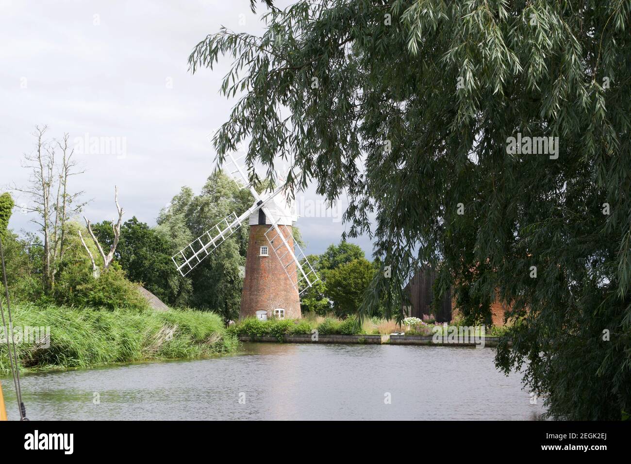 A traditional windmill (wind pump) at a bend in a tranquil river. Built ...