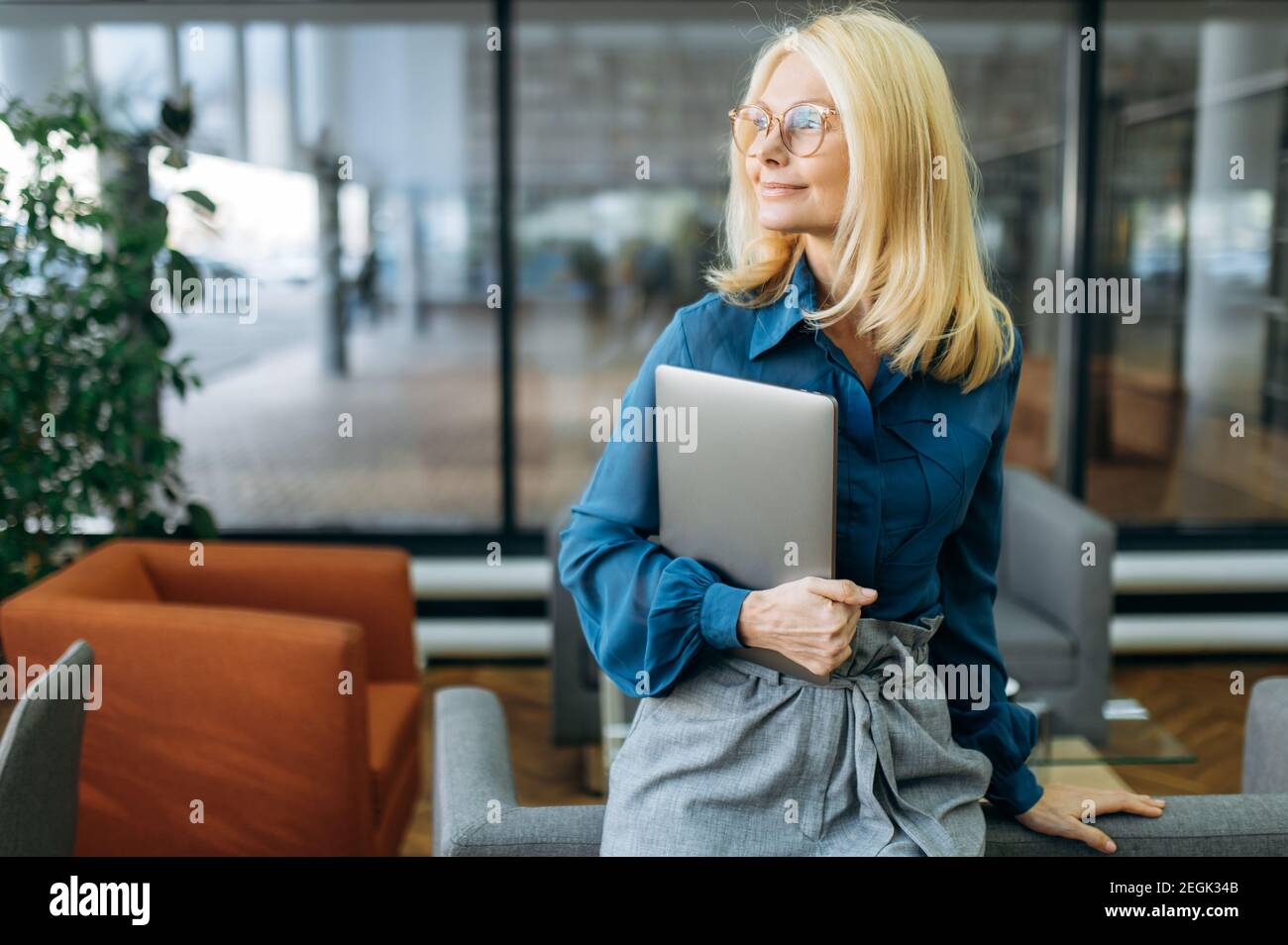 Confident intelligent business woman stands in modern office, looks by ...