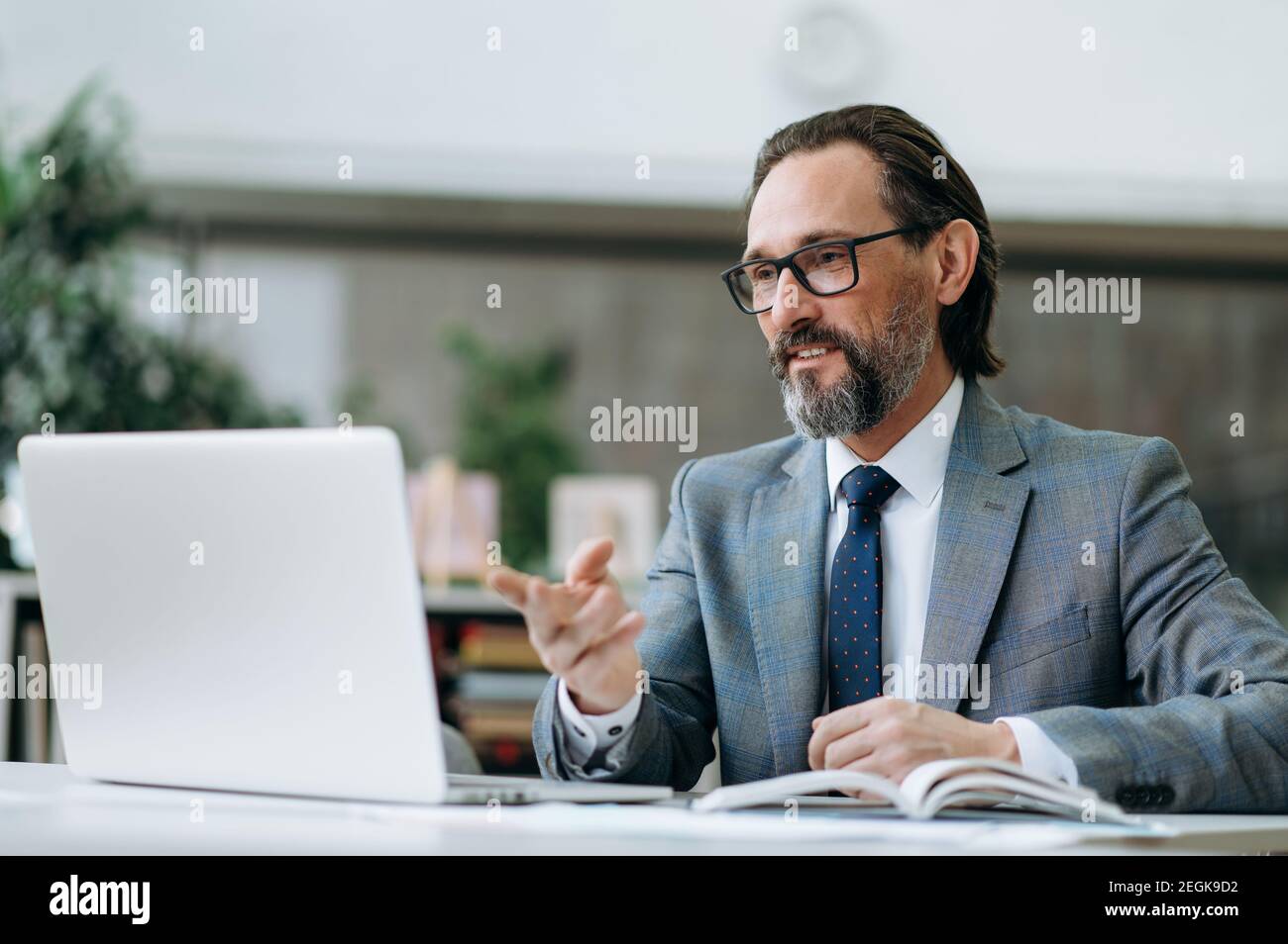 Elegant senior businessman is having a conversation on video conference ...