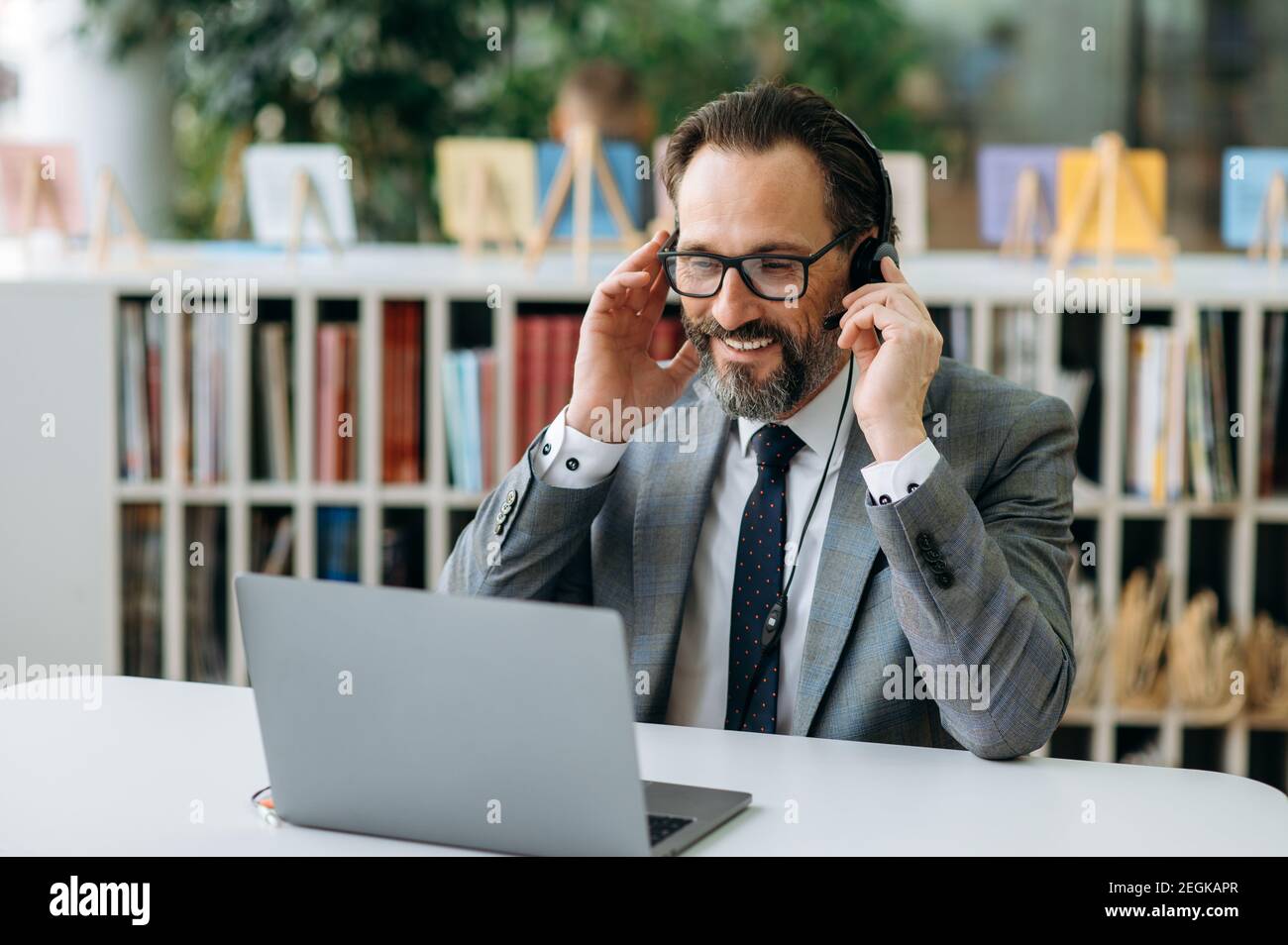 Smiling male operator of call center in headphones communicate with ...