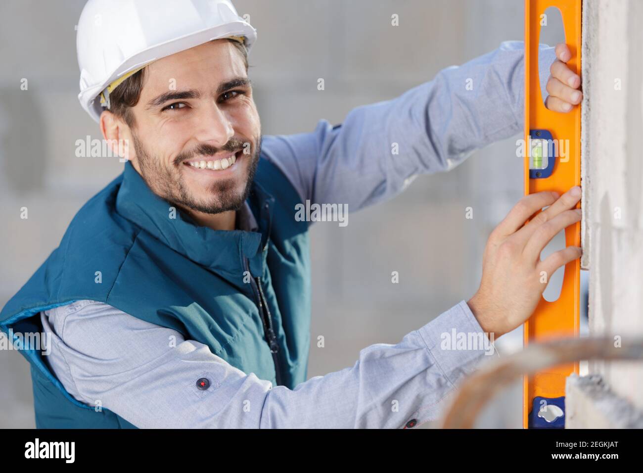 construction worker with spirit level in front of construction site ...