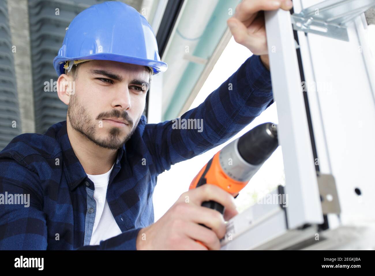 workman using torque screwdriver installing metal on new window frame ...