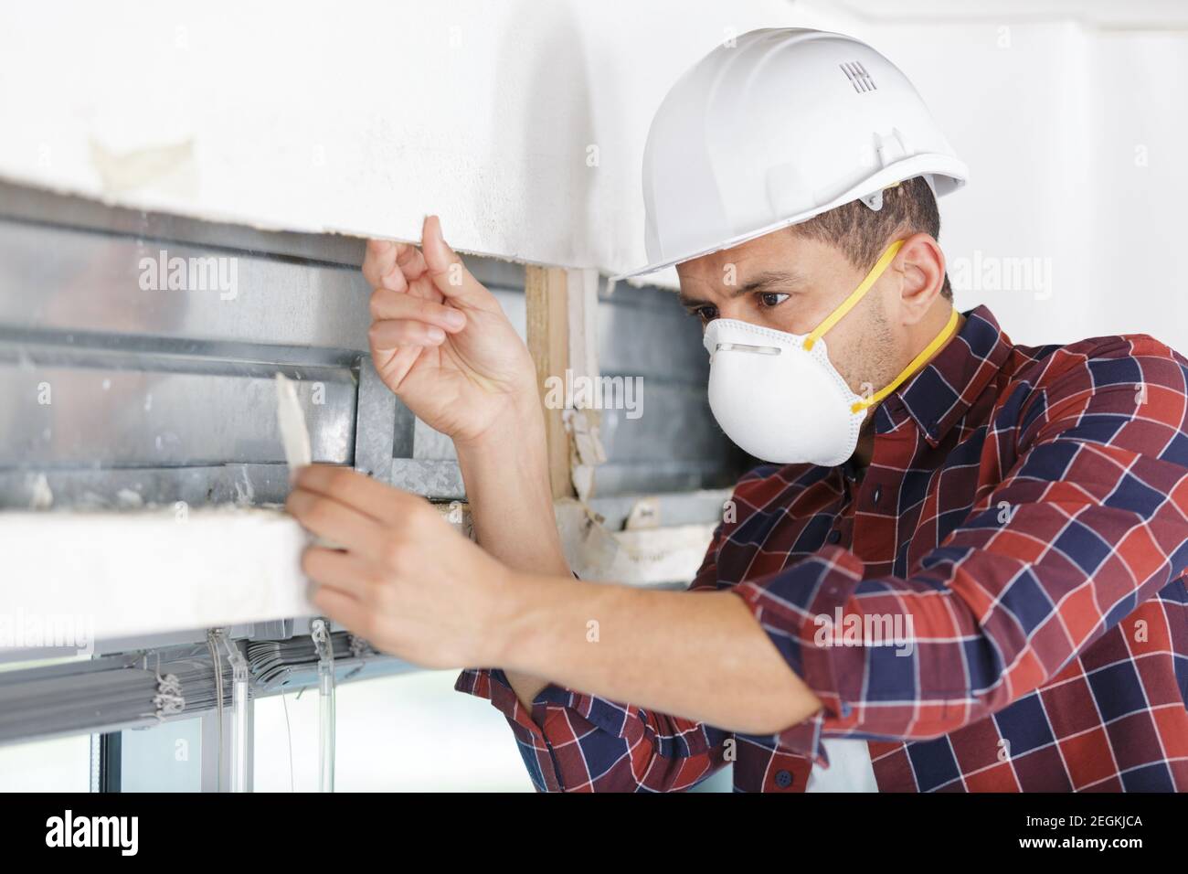 man in helmet and mask is checking wall isolation Stock Photo - Alamy