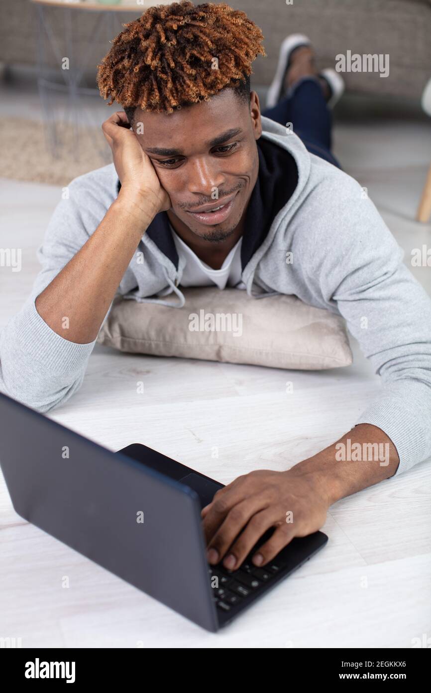 attractive smiling chill guy is browsing at his laptop Stock Photo - Alamy