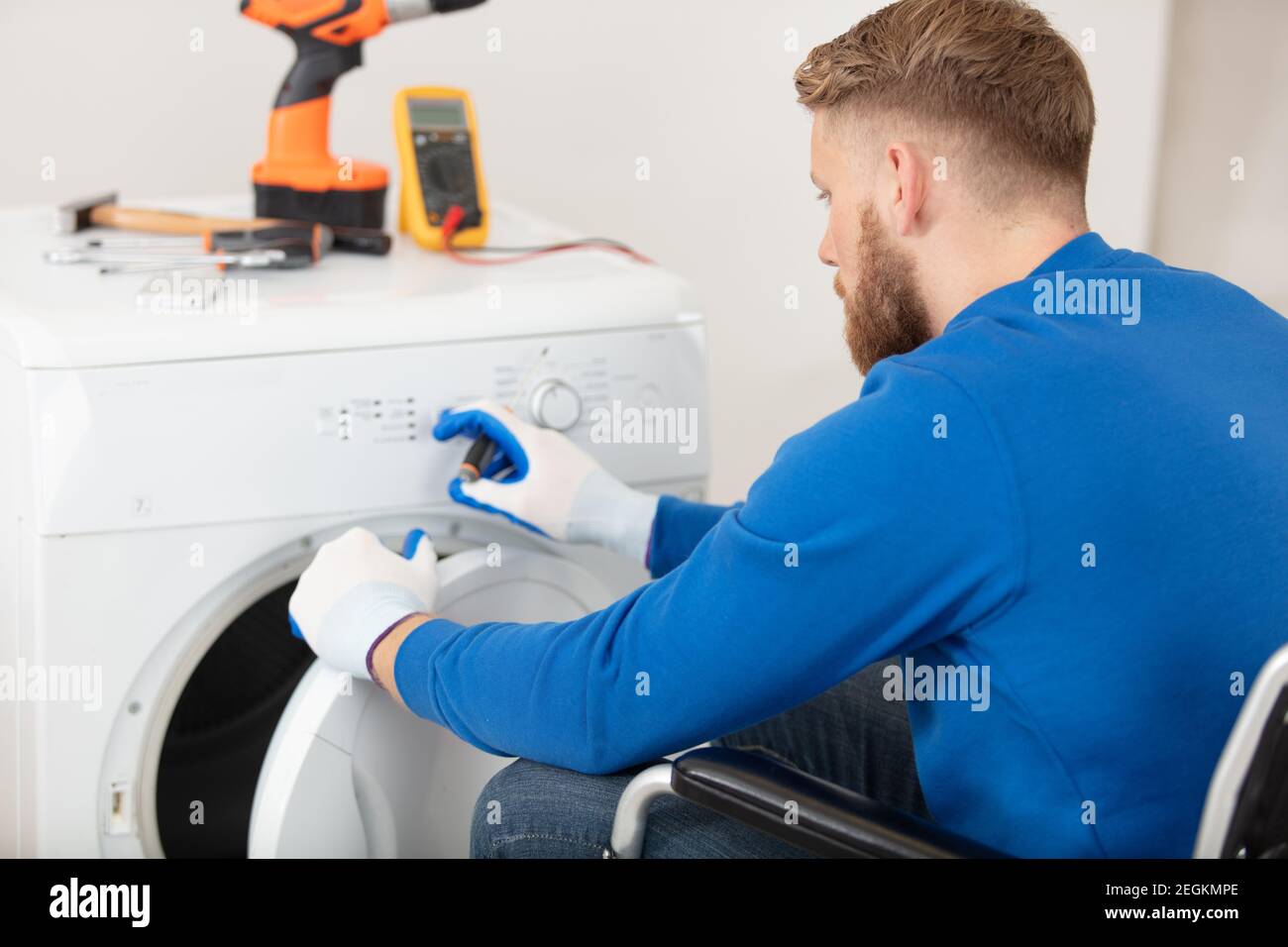 man in wheelchair repairing a washing machine Stock Photo - Alamy