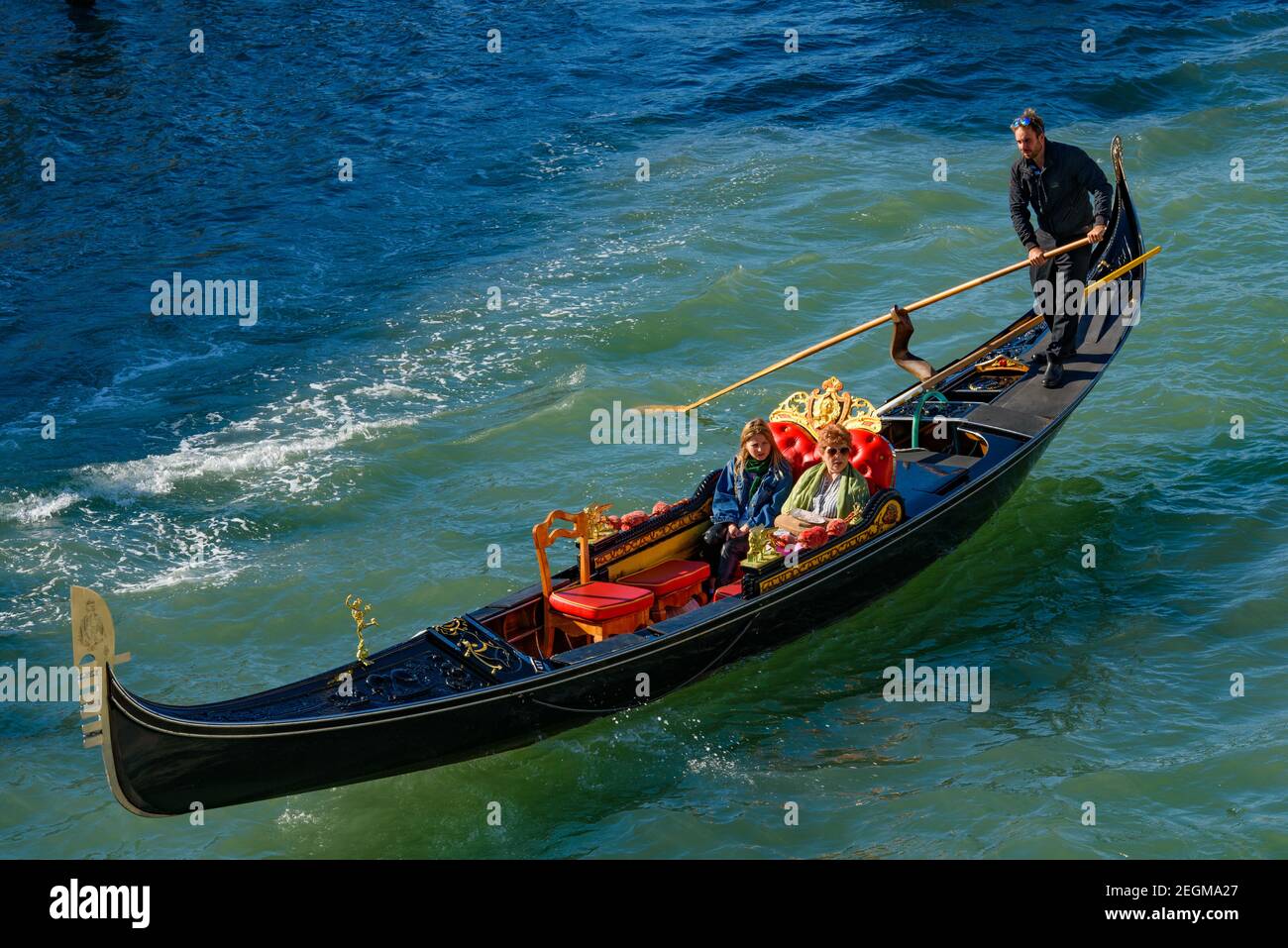 Tourists taking gondola, the traditional Venetian boat, on canal in ...