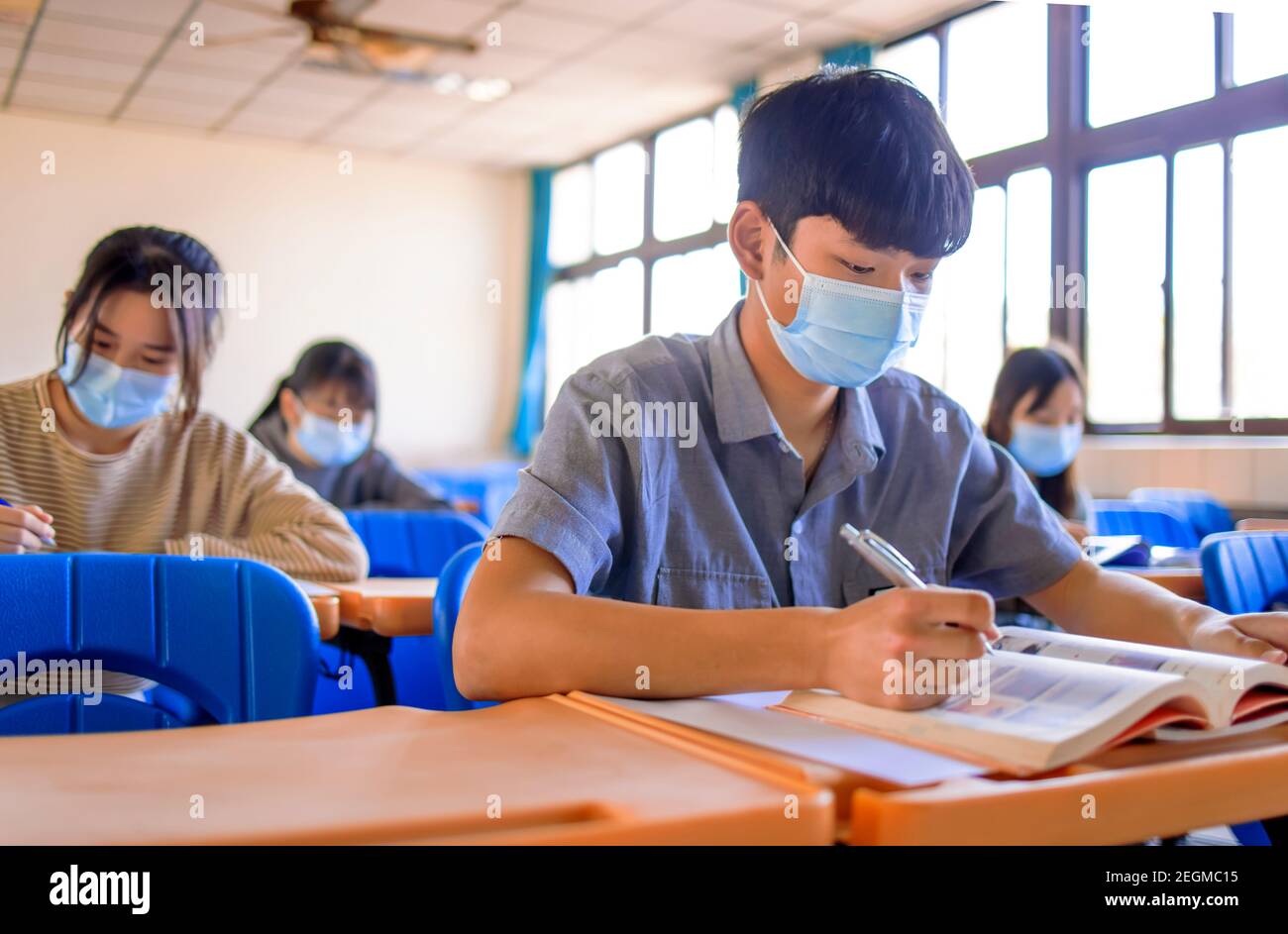 Group of students wearing protection masks and studying in classroom ...