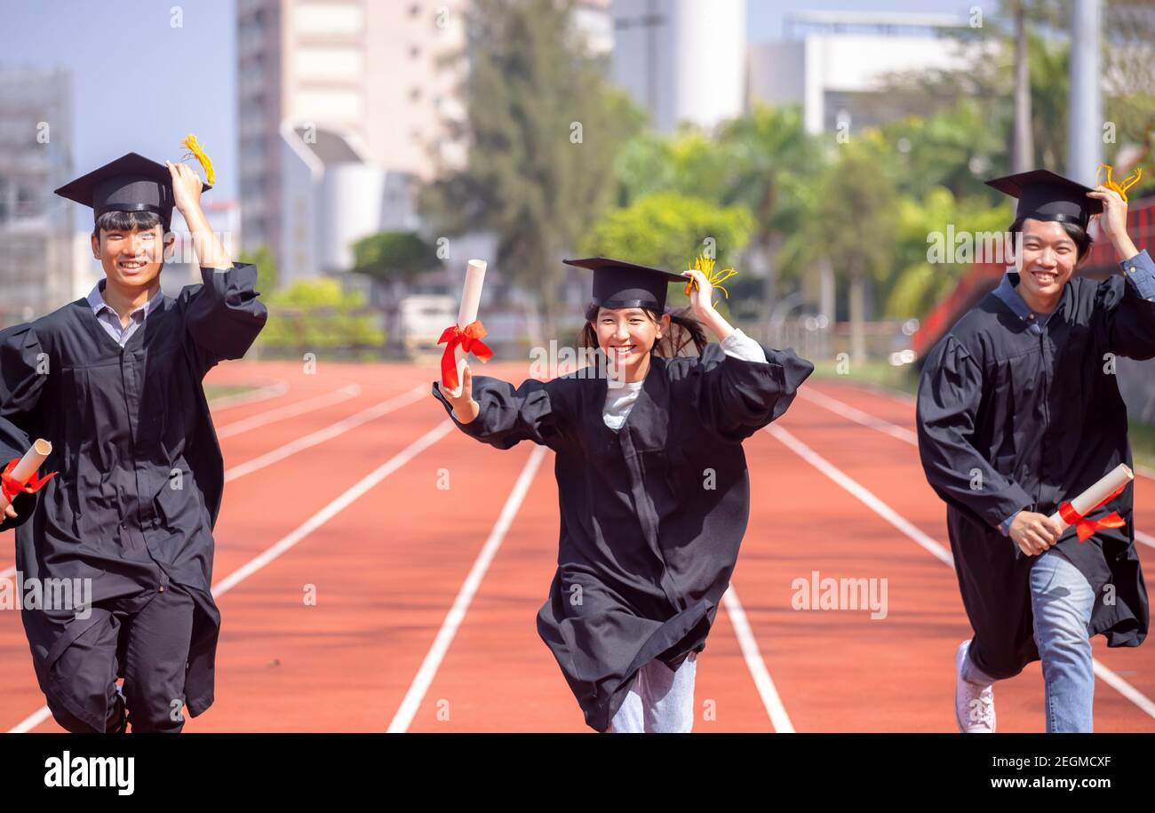 happy graduation students holding diploma and running on the stadium at ...