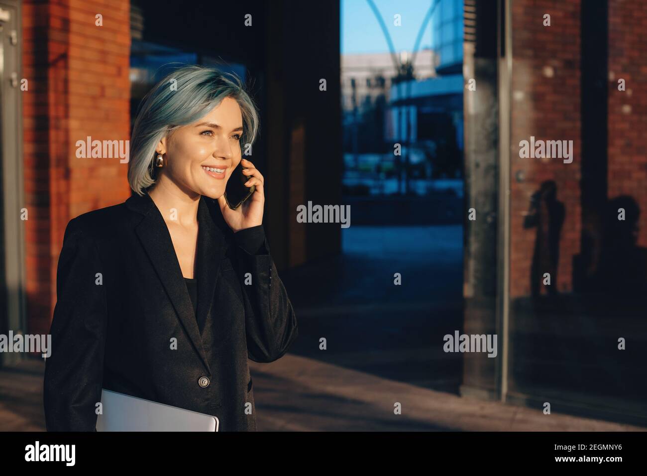Young businesswoman talking on phone and smile while walking with a ...