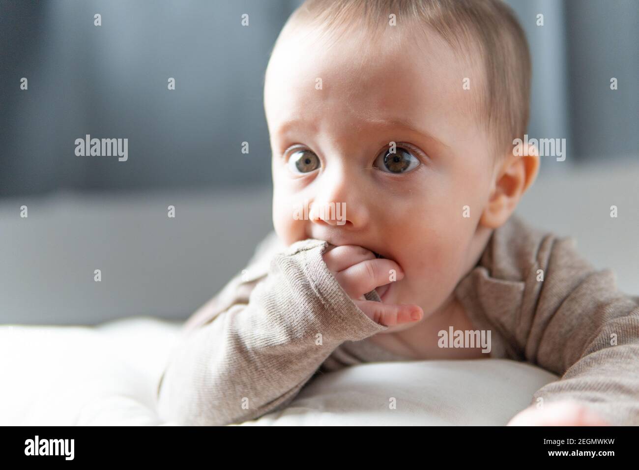 very cute six month old baby eating his hand. dentition Stock Photo - Alamy