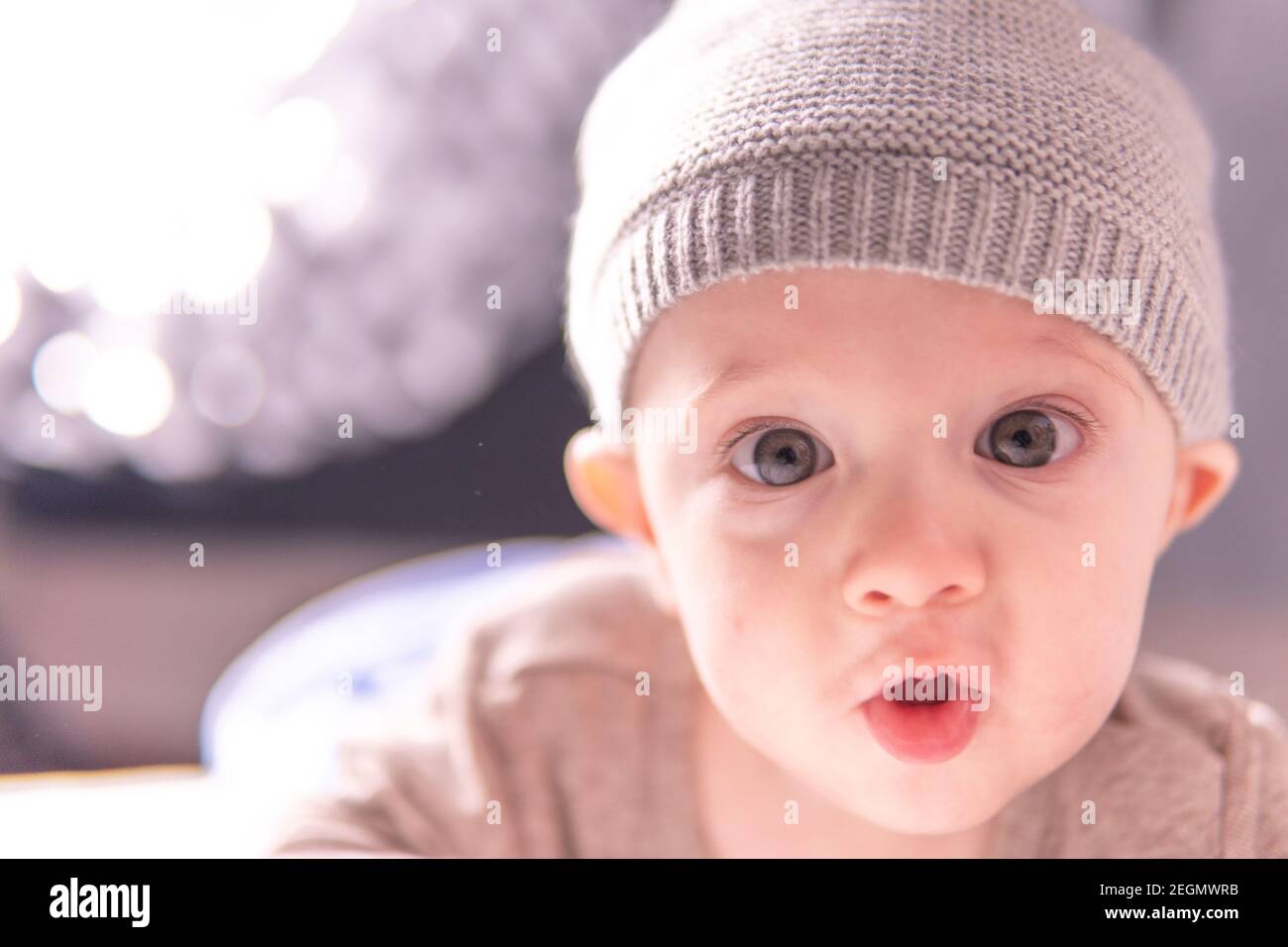 six month old baby with curious face with hat looking straight ahead ...