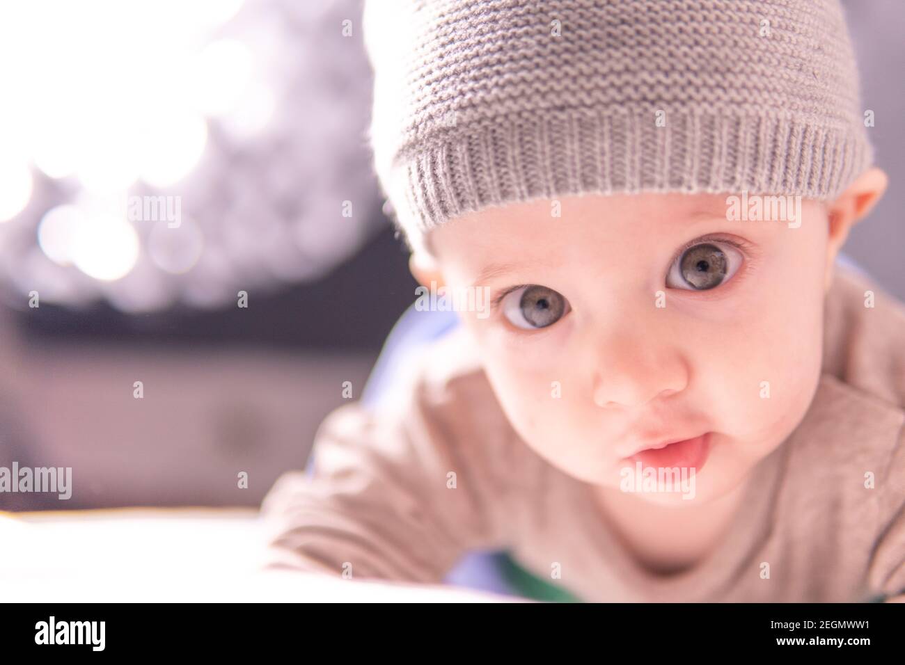 six month old baby with curious face with hat looking straight ahead ...