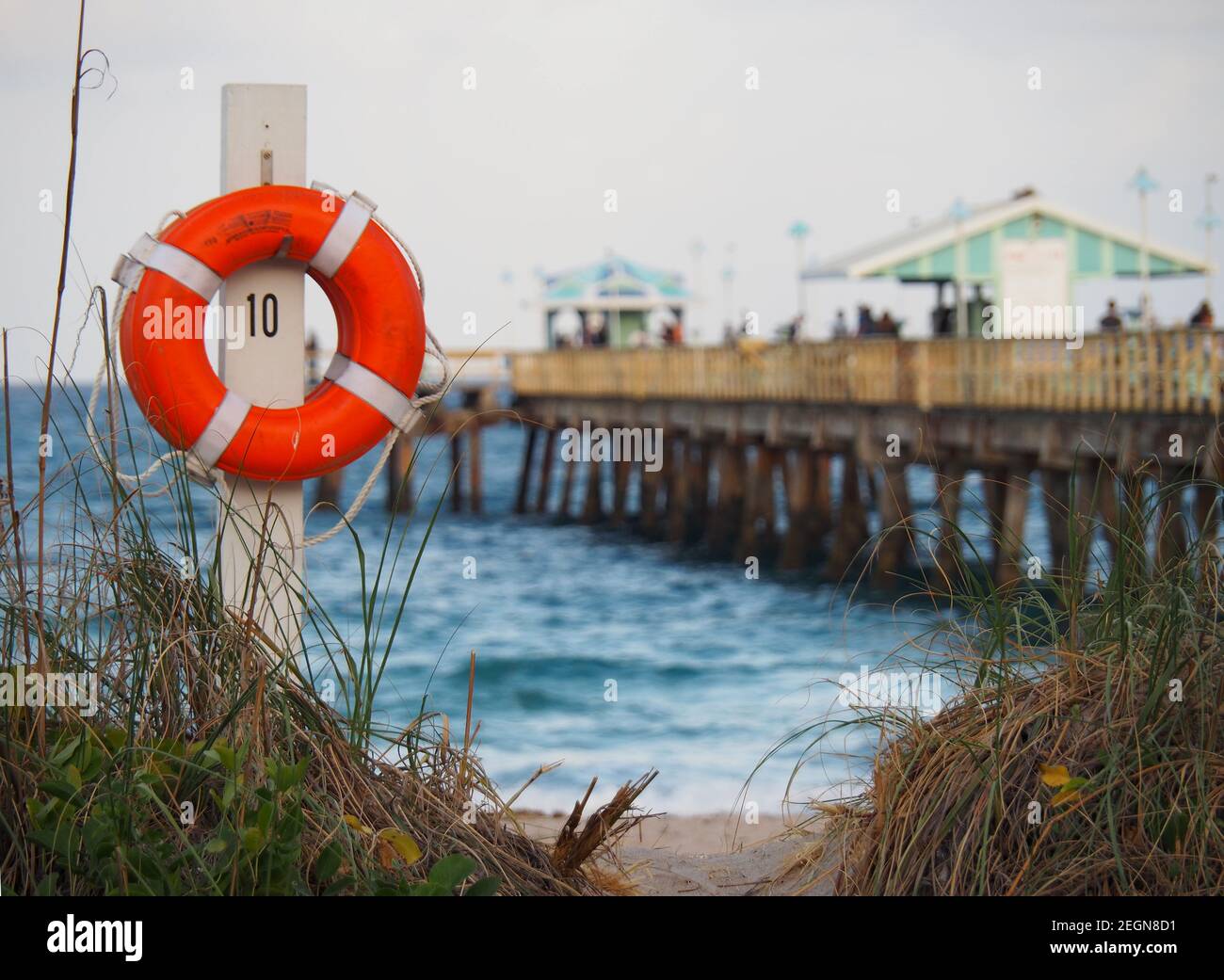 Beach access next to pier and lifeguard float hanging from pole at the ...
