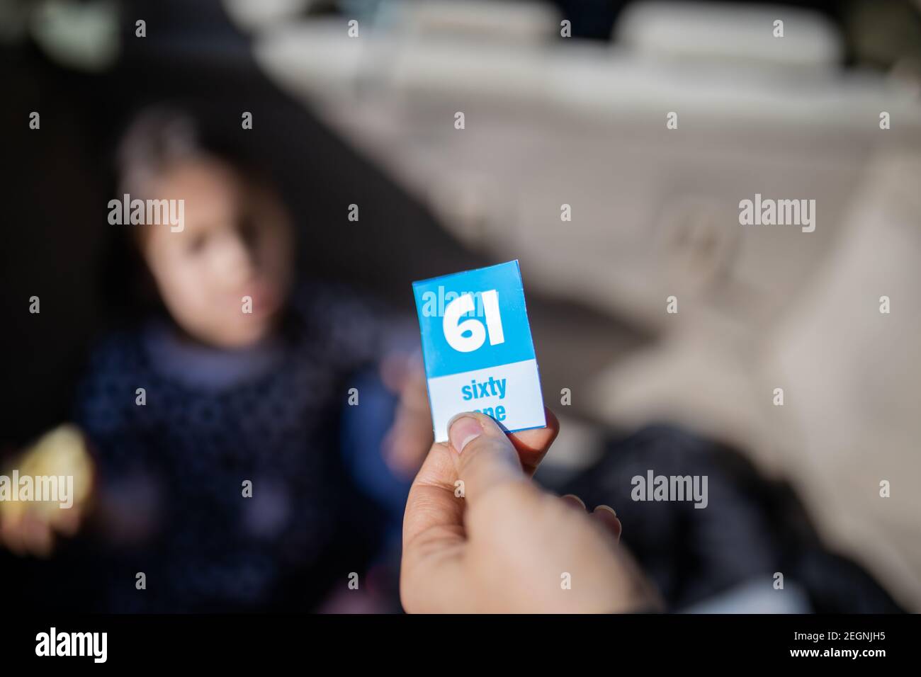 Female hand holding a card with the number 61 with blurry background ...
