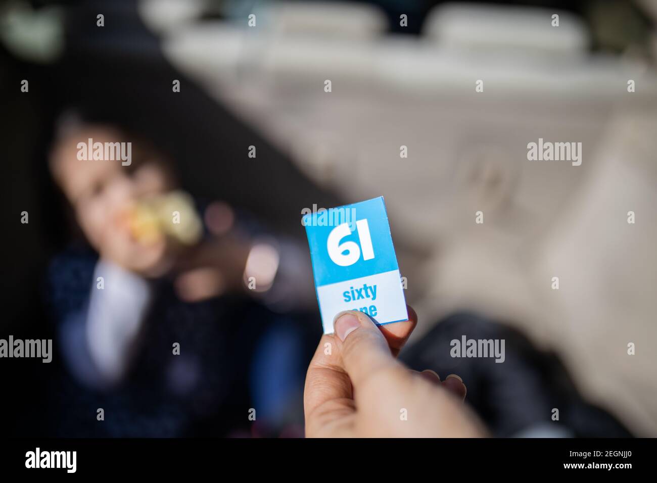 Female hand holding a card with the number 61 with blurry background ...