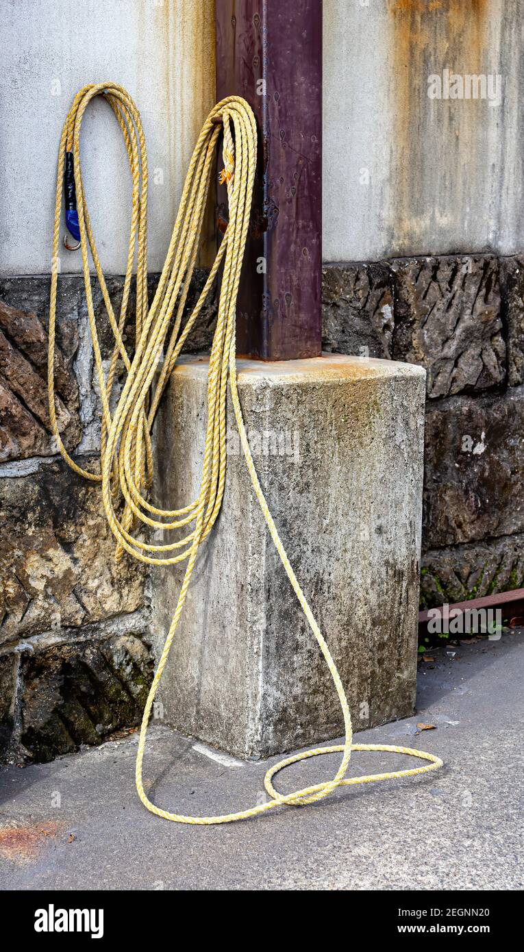 An uncoiled rope hangs from a bolt of a steel beam, ready to be used ...
