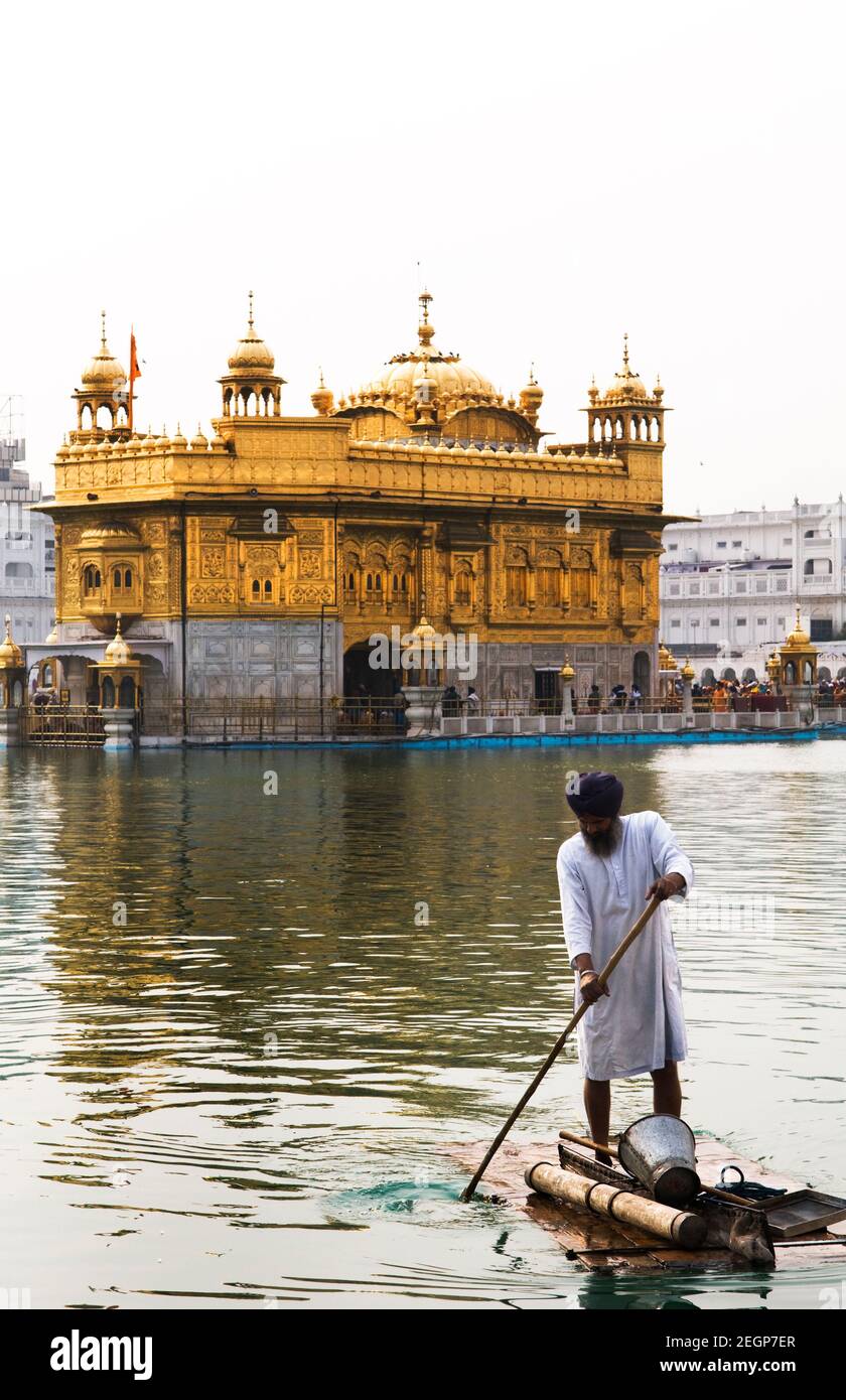 A Sikh man on a small raft cleaning the water tank around the Golden ...